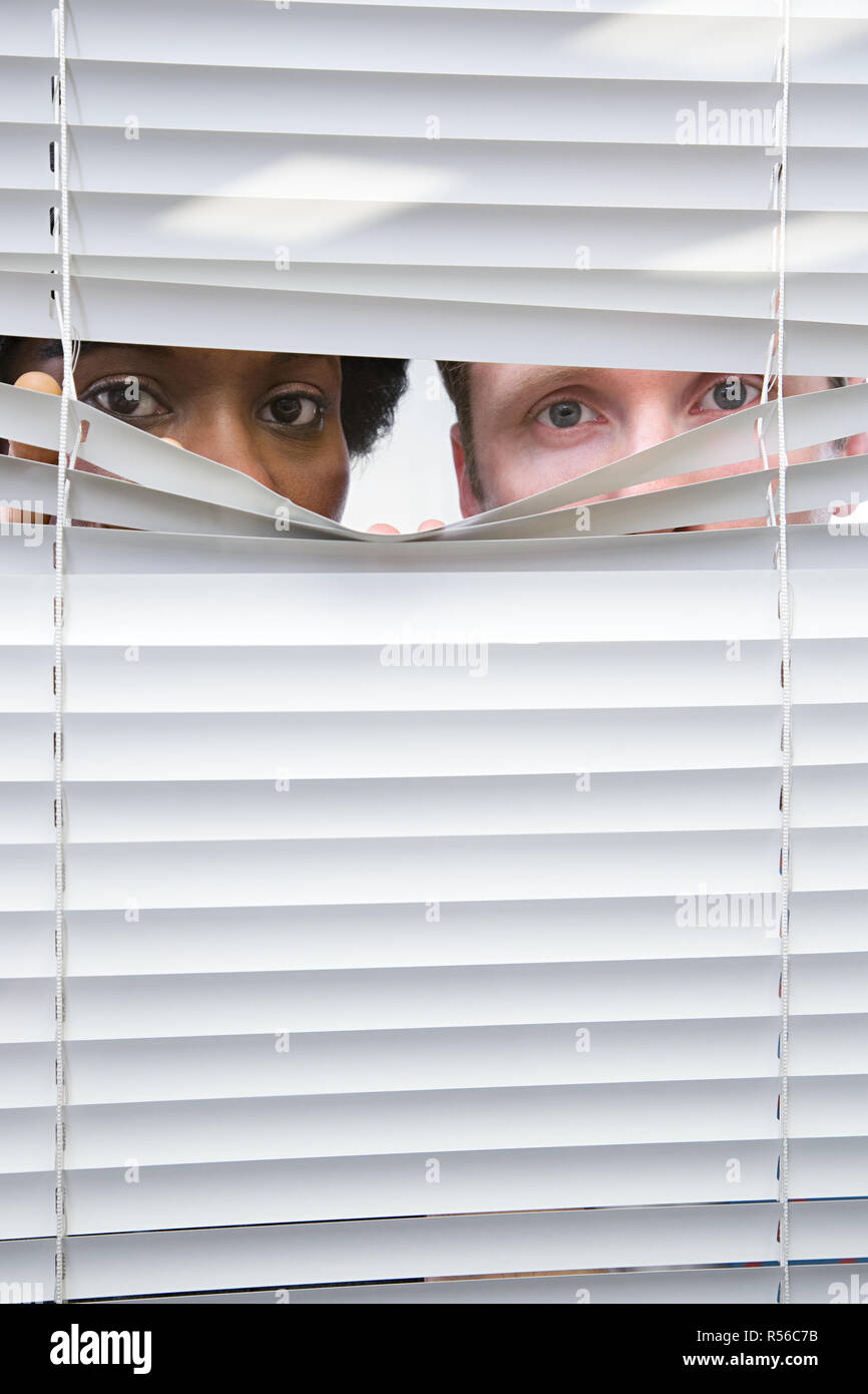 Colleagues looking through blinds Stock Photo - Alamy