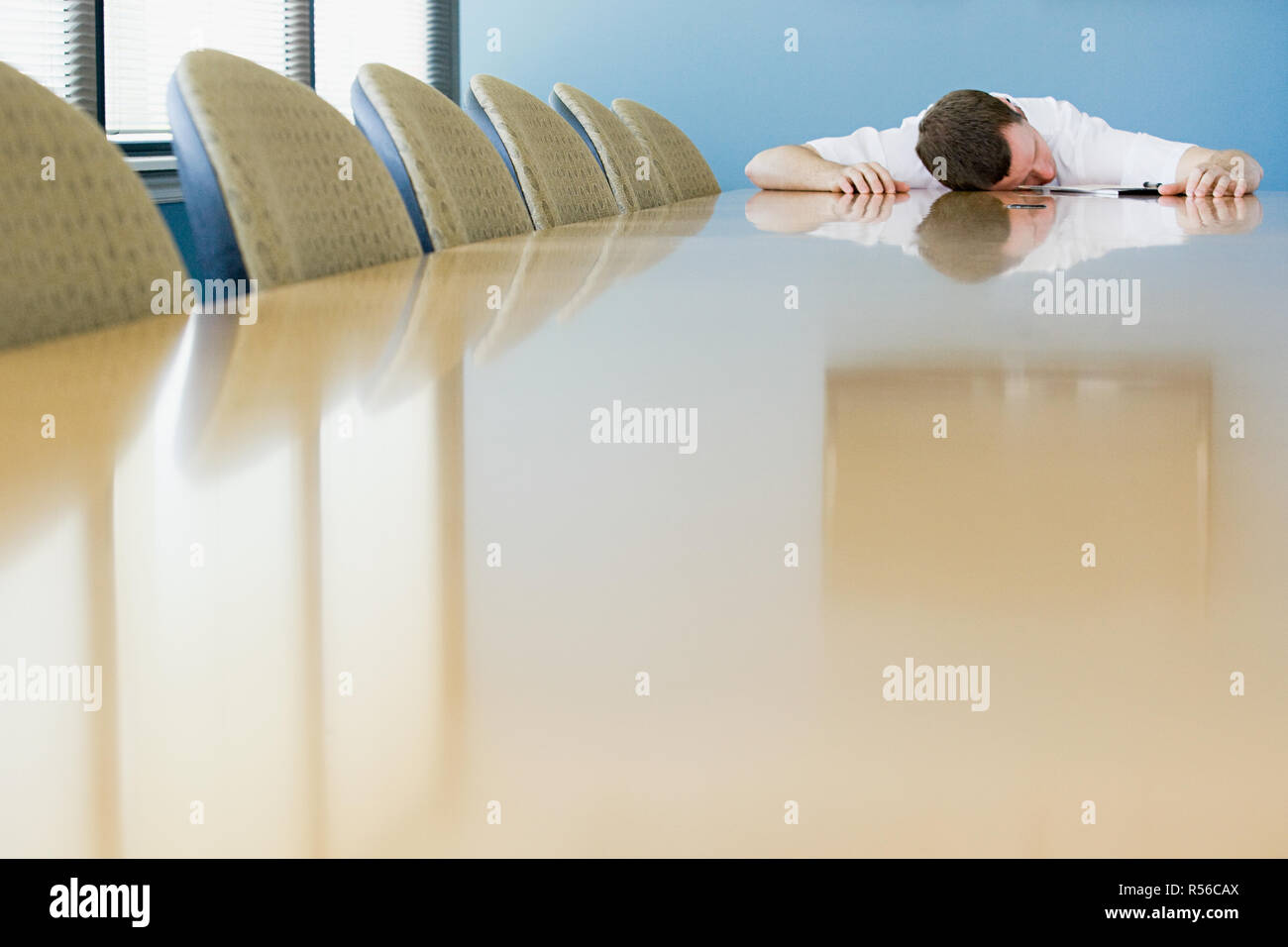Man sleeping on conference table Stock Photo - Alamy