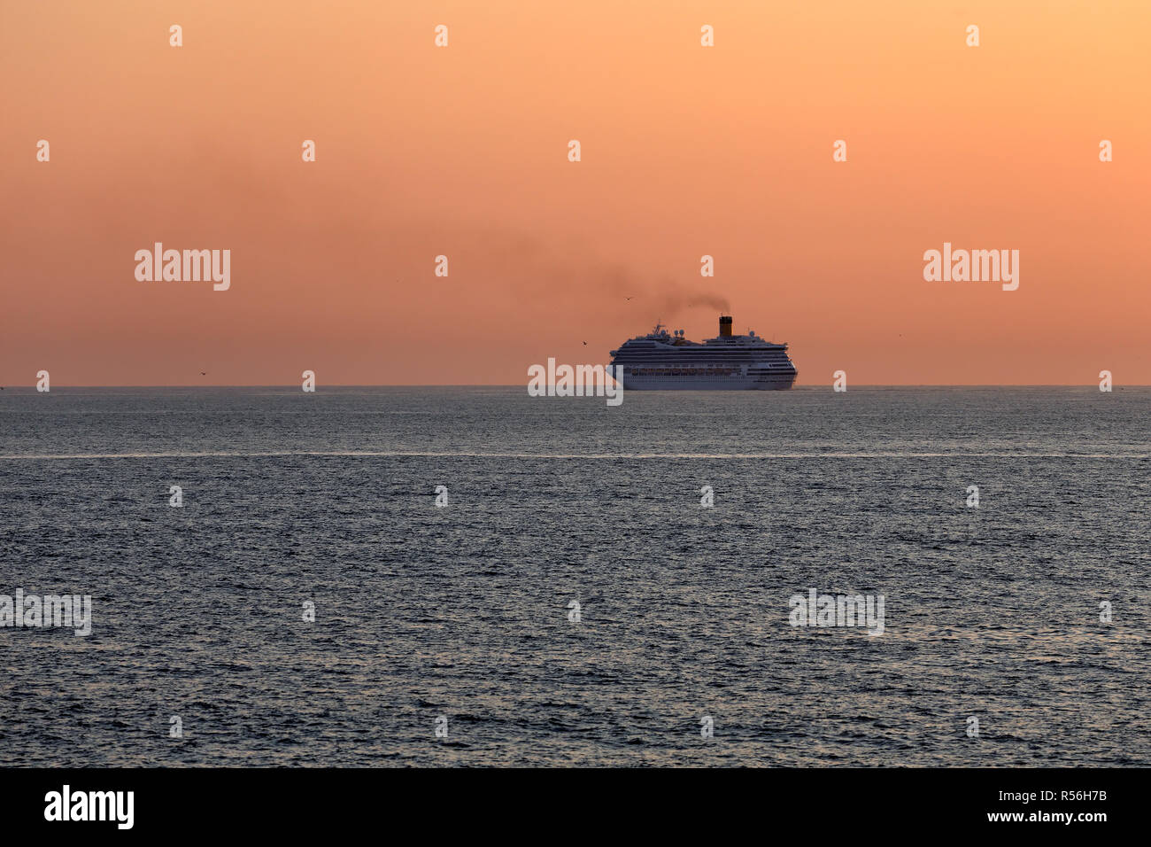 Passenger ship on the horizon by a beautiful orange sunset Stock Photo ...