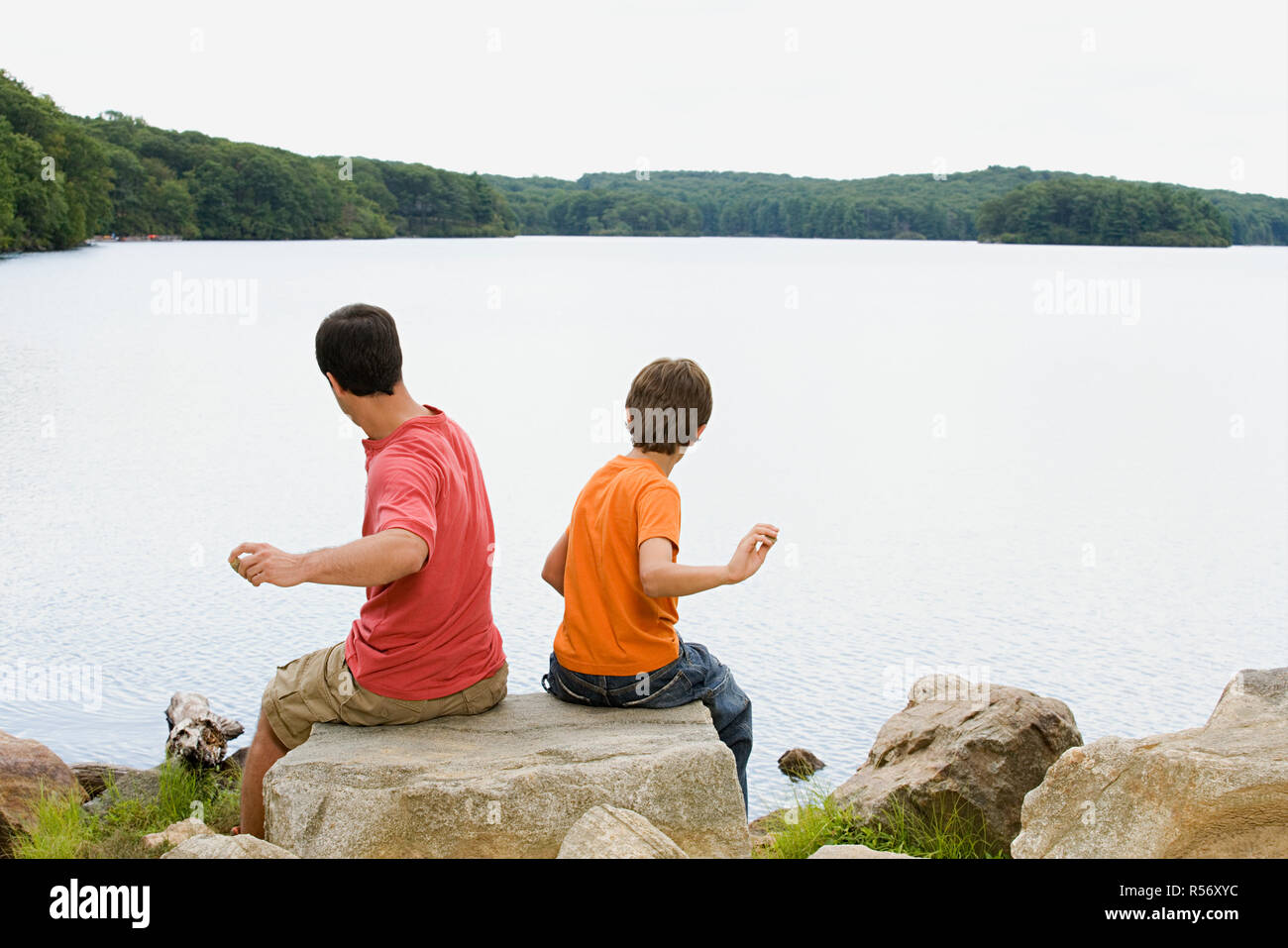 Father and son throwing rocks into lake Stock Photo - Alamy