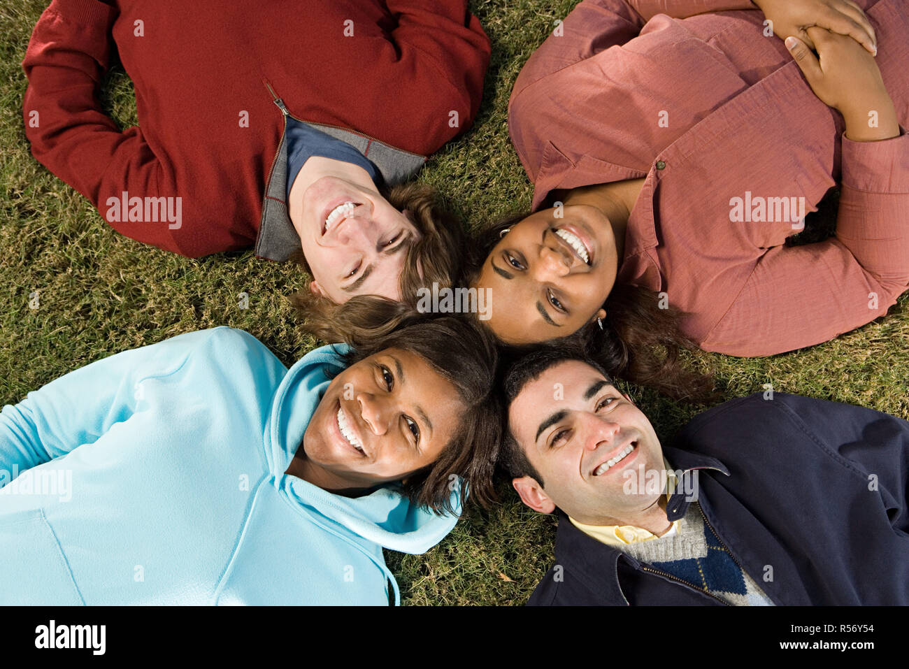 Four students lying down outdoors Stock Photo - Alamy