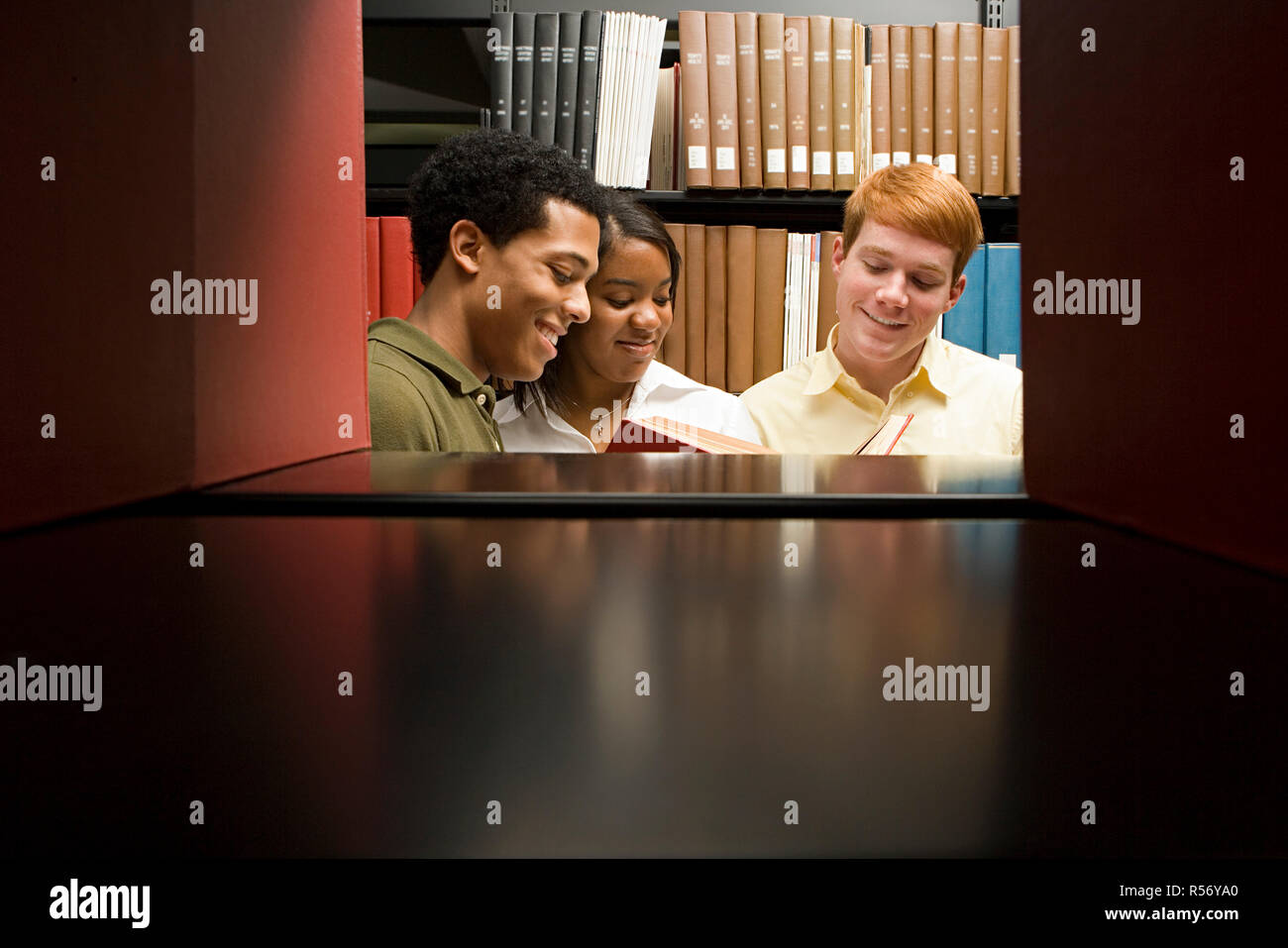 Three students reading in the library Stock Photo - Alamy