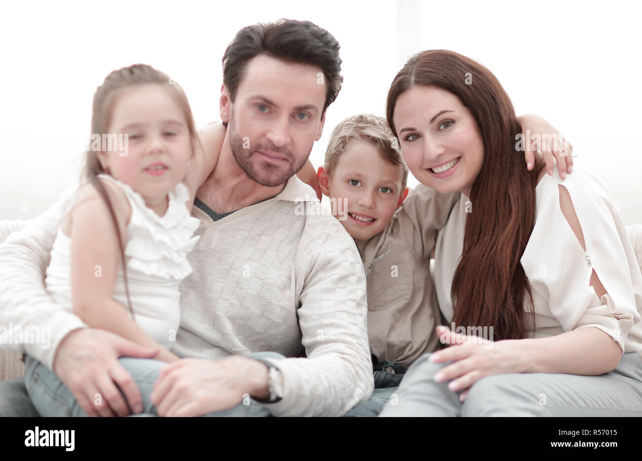 parents hug their children sitting on the couch Stock Photo - Alamy