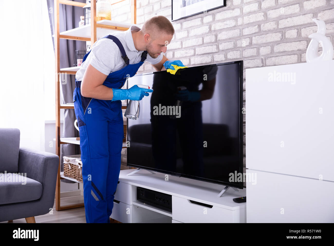 Young Male Janitor Cleaning Television With Soft Cloth Stock Photo - Alamy