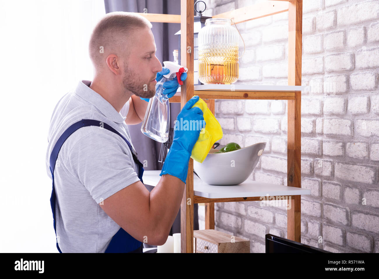 Side View Of A Young Male Janitor Cleaning Shelf In House Stock Photo ...