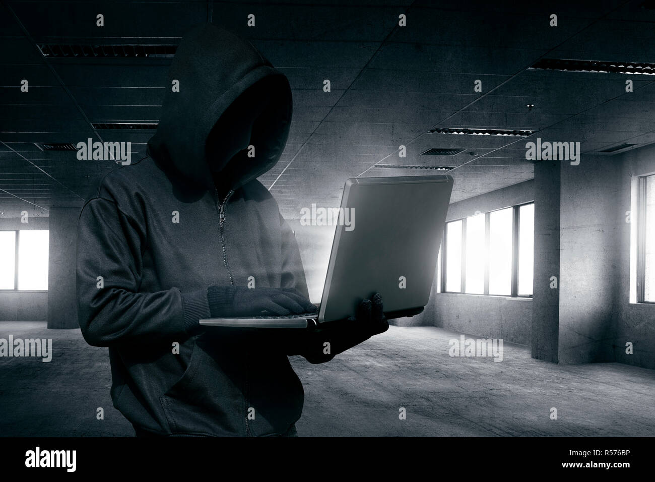 Hooded man with mask using laptop to hacking Stock Photo - Alamy