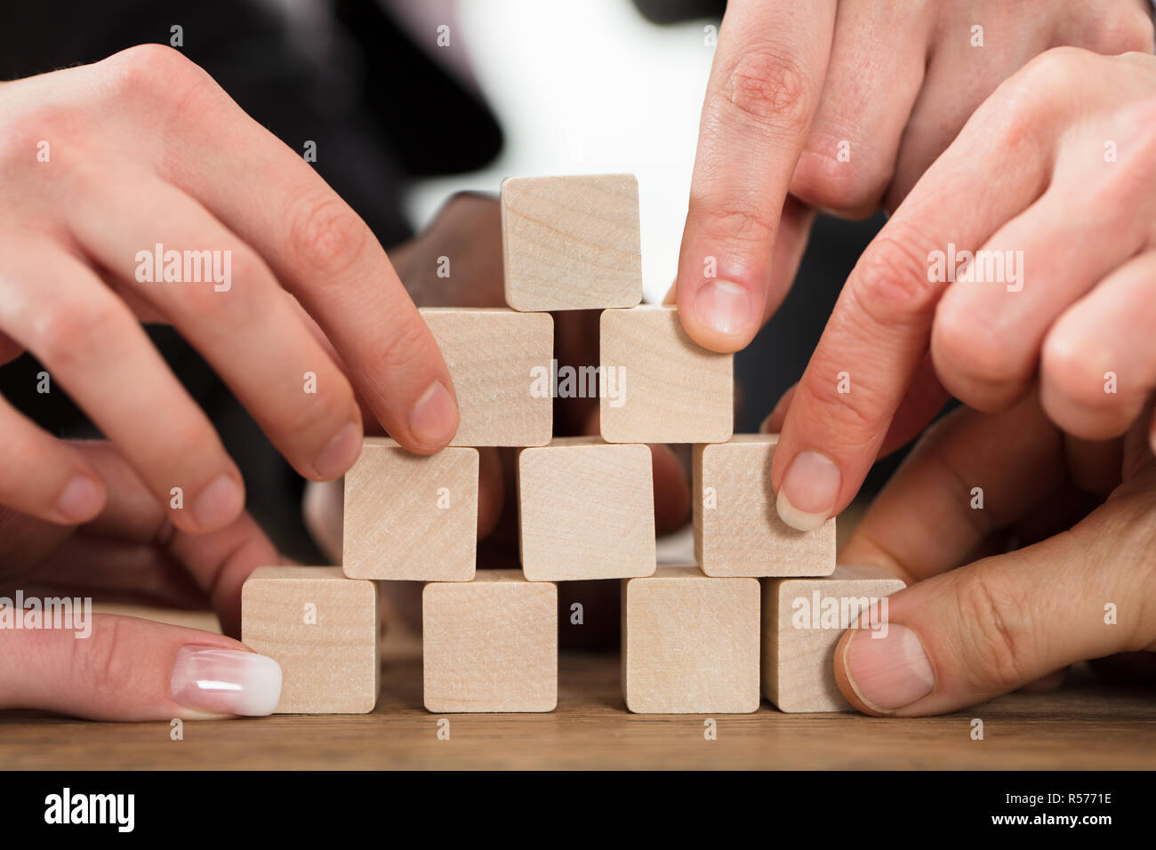 People Arranging Block On Pyramid Stock Photo - Alamy
