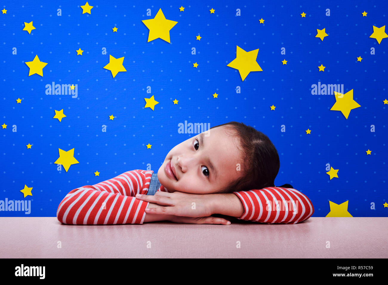 Smiling asian child resting on desk Stock Photo - Alamy