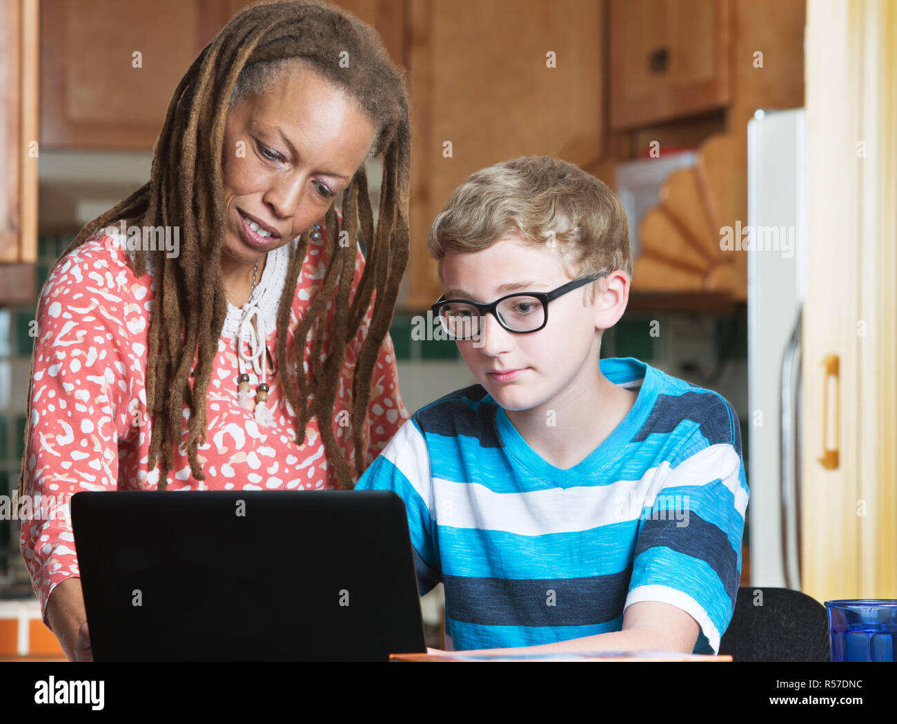 Child doing homework with foster parent in kitchen Stock Photo - Alamy