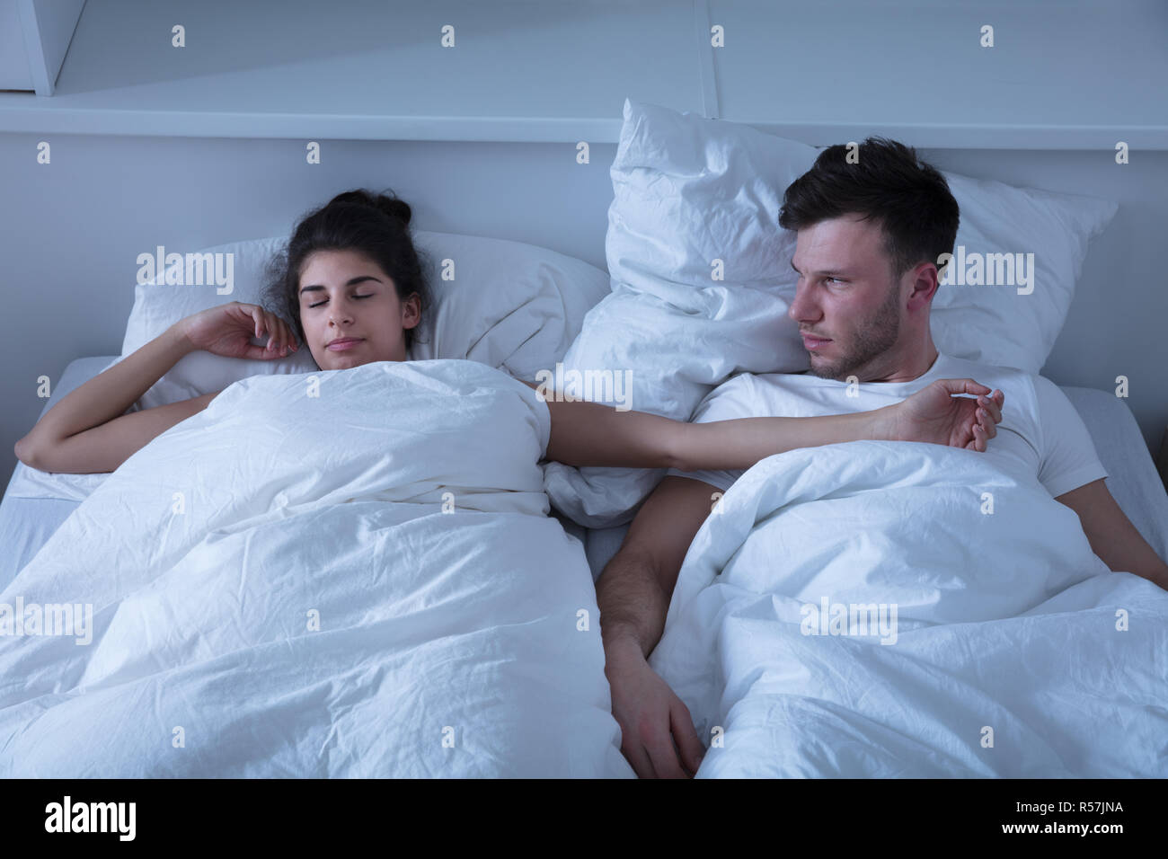 Angry Man Looking At Her Wife Sleeping On Bed Stock Photo - Alamy