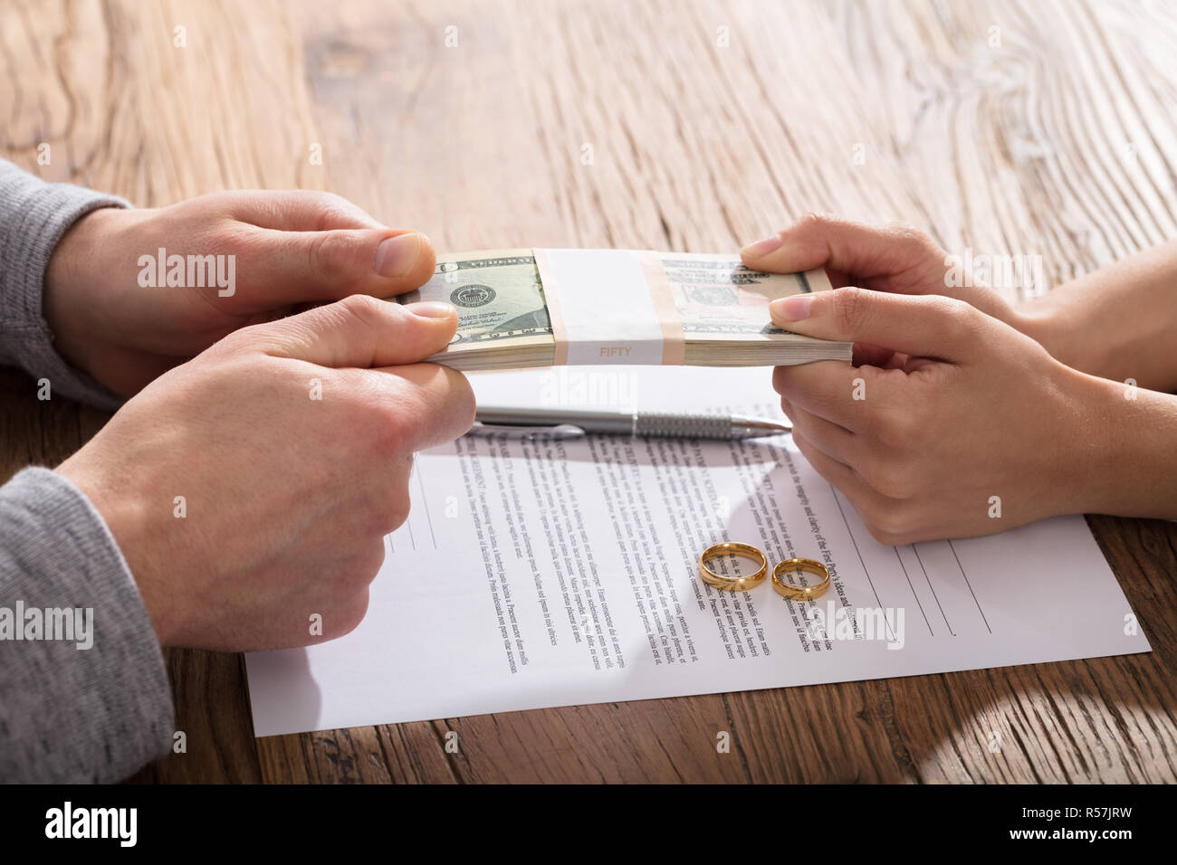 Couple's Hand Holding Currency Over The Divorce Agreement Stock Photo ...