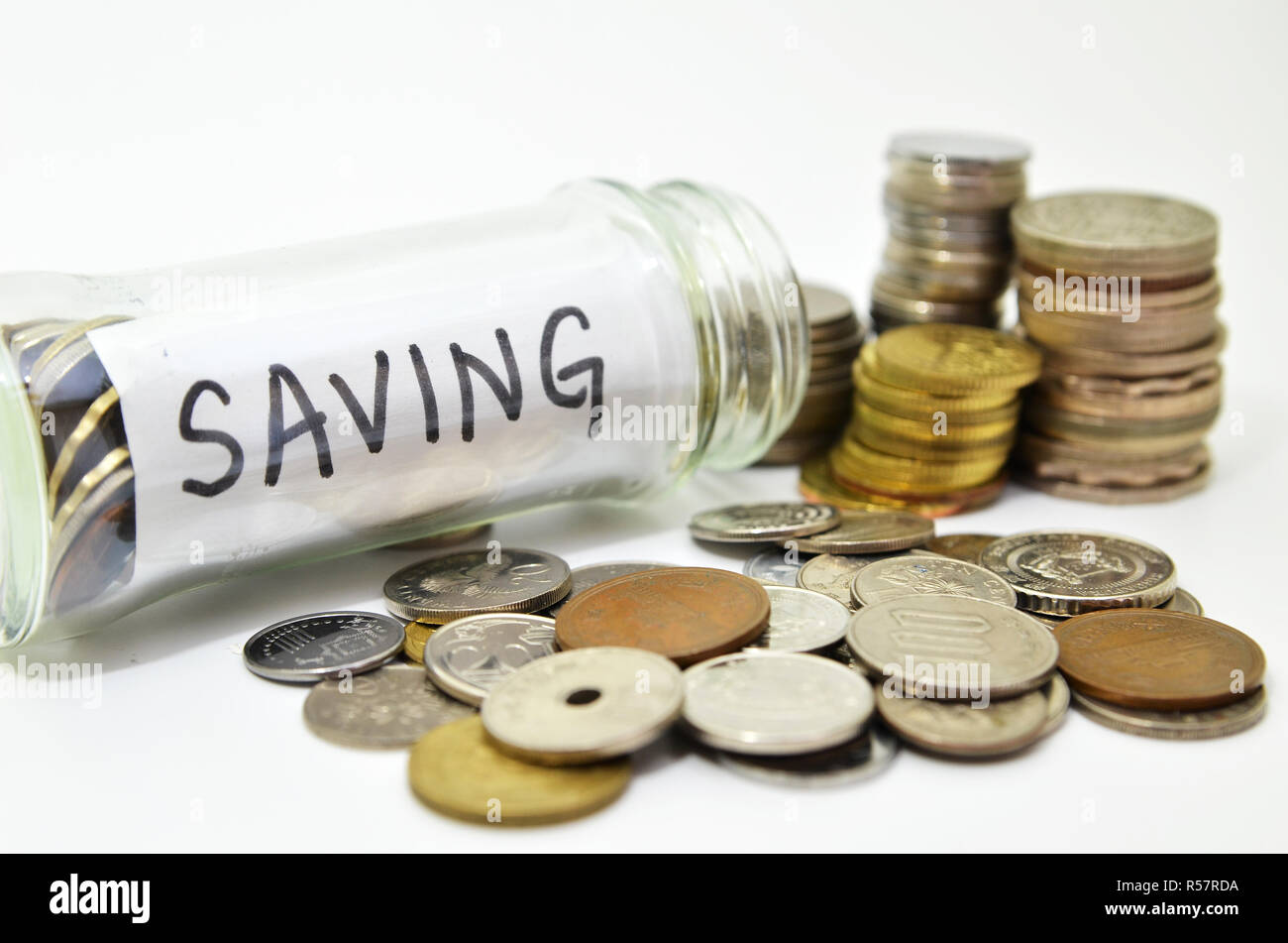 Saving lable in a glass jar with coins spilling out Stock Photo - Alamy