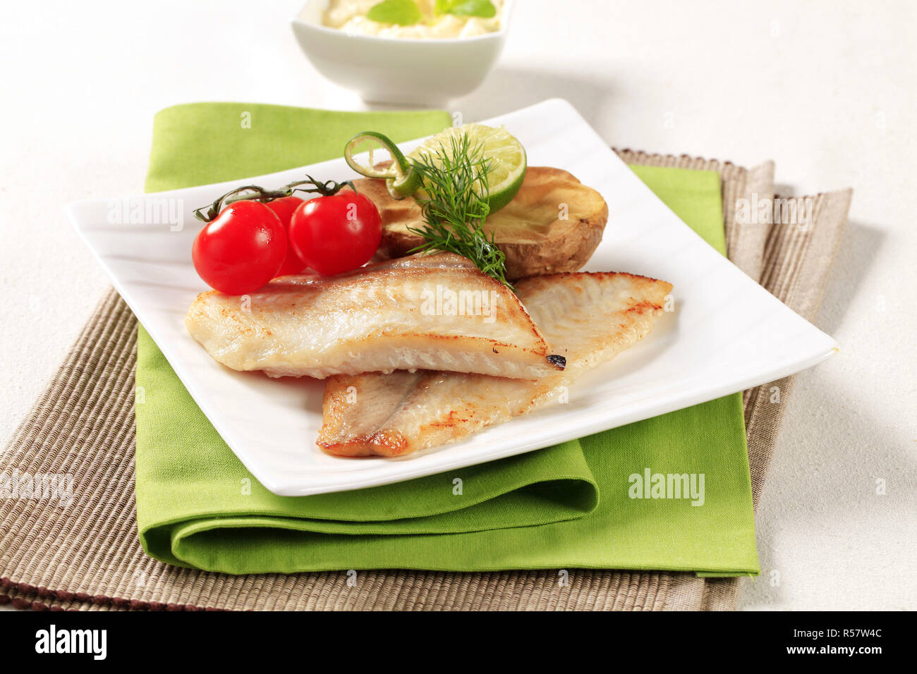 Skinless fish fillets with baked potato half Stock Photo - Alamy