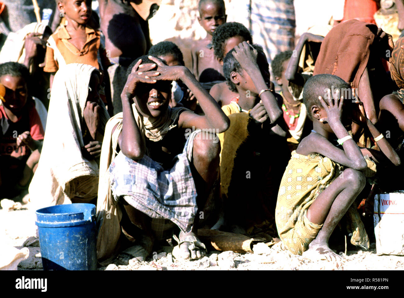 Somalians sit in the sun as they wait for food provided during ...