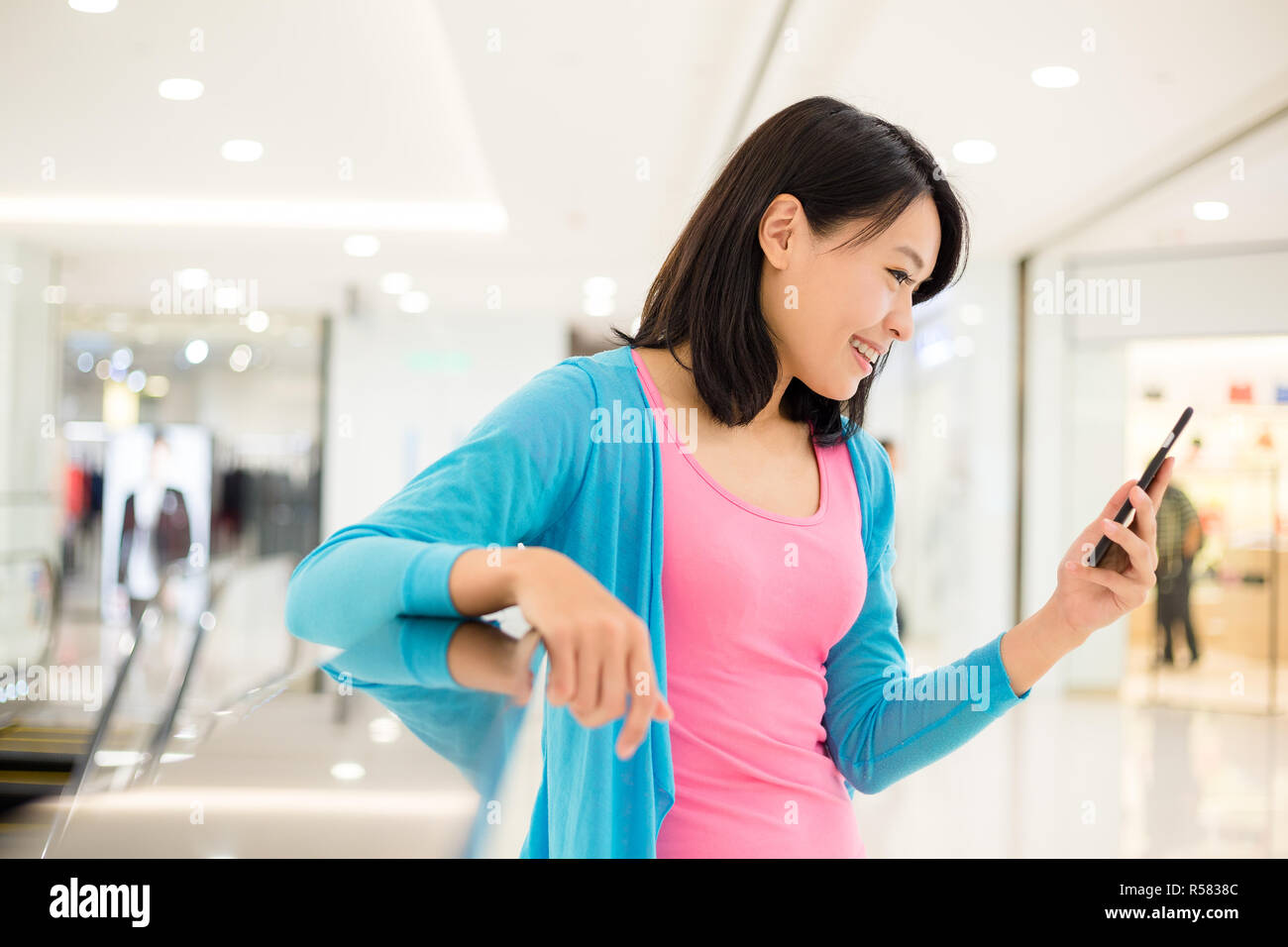 Woman using cellphone inside shopping mall Stock Photo - Alamy