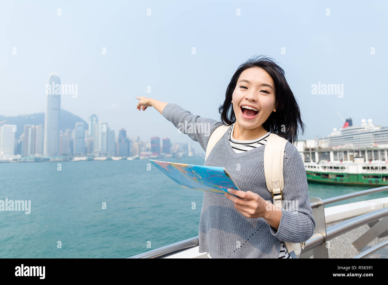 Woman pointing far away with paper map Stock Photo - Alamy