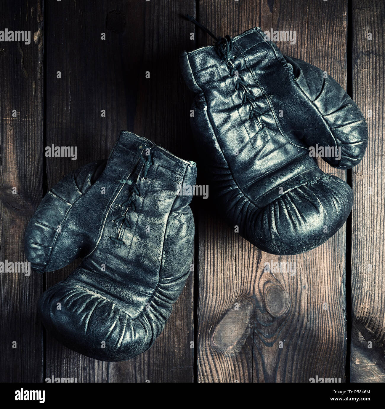 pair of black leather very old boxing gloves on a brown wooden ...