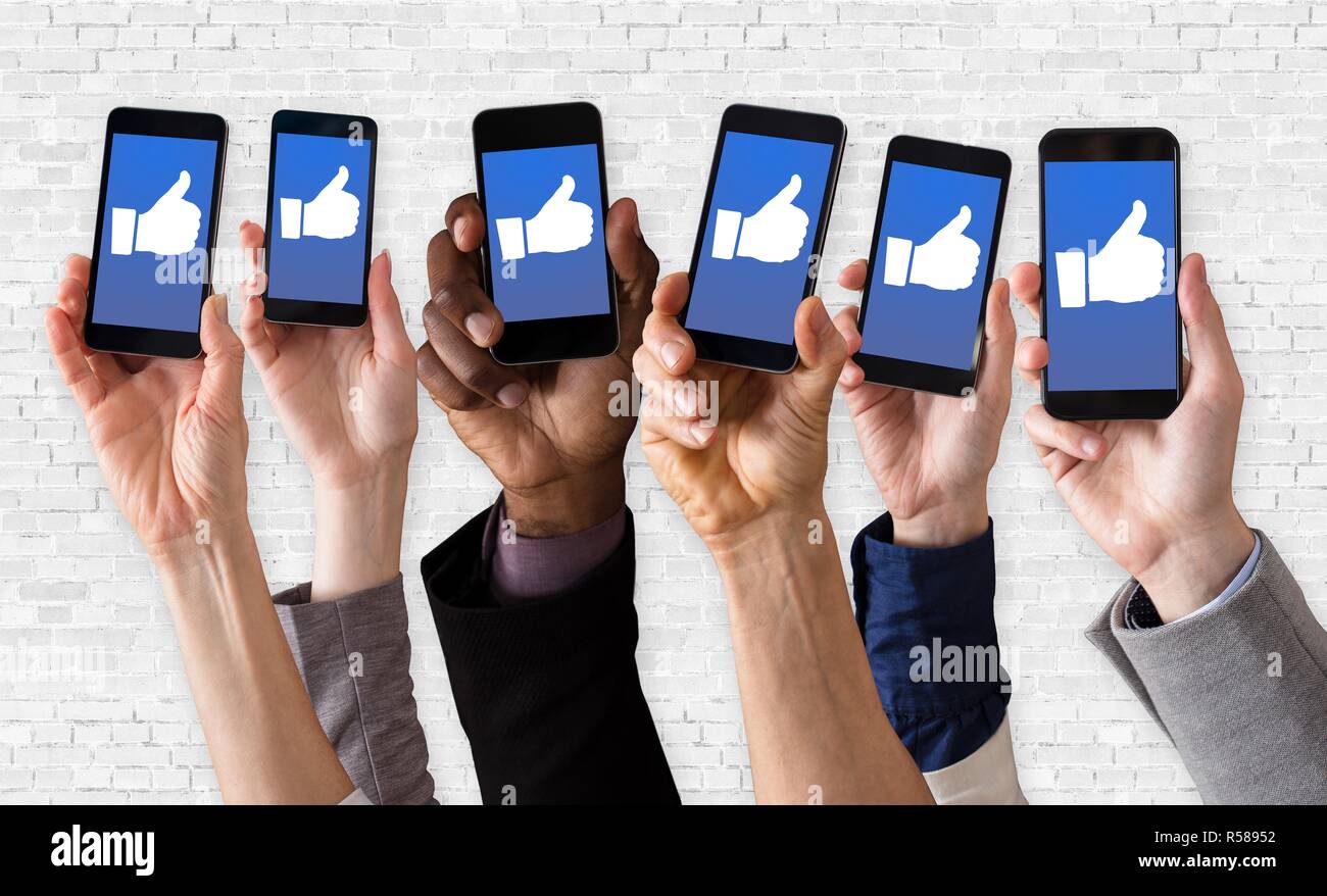 Hands Showing Thumb Up Symbol On Mobile Screens Stock Photo - Alamy