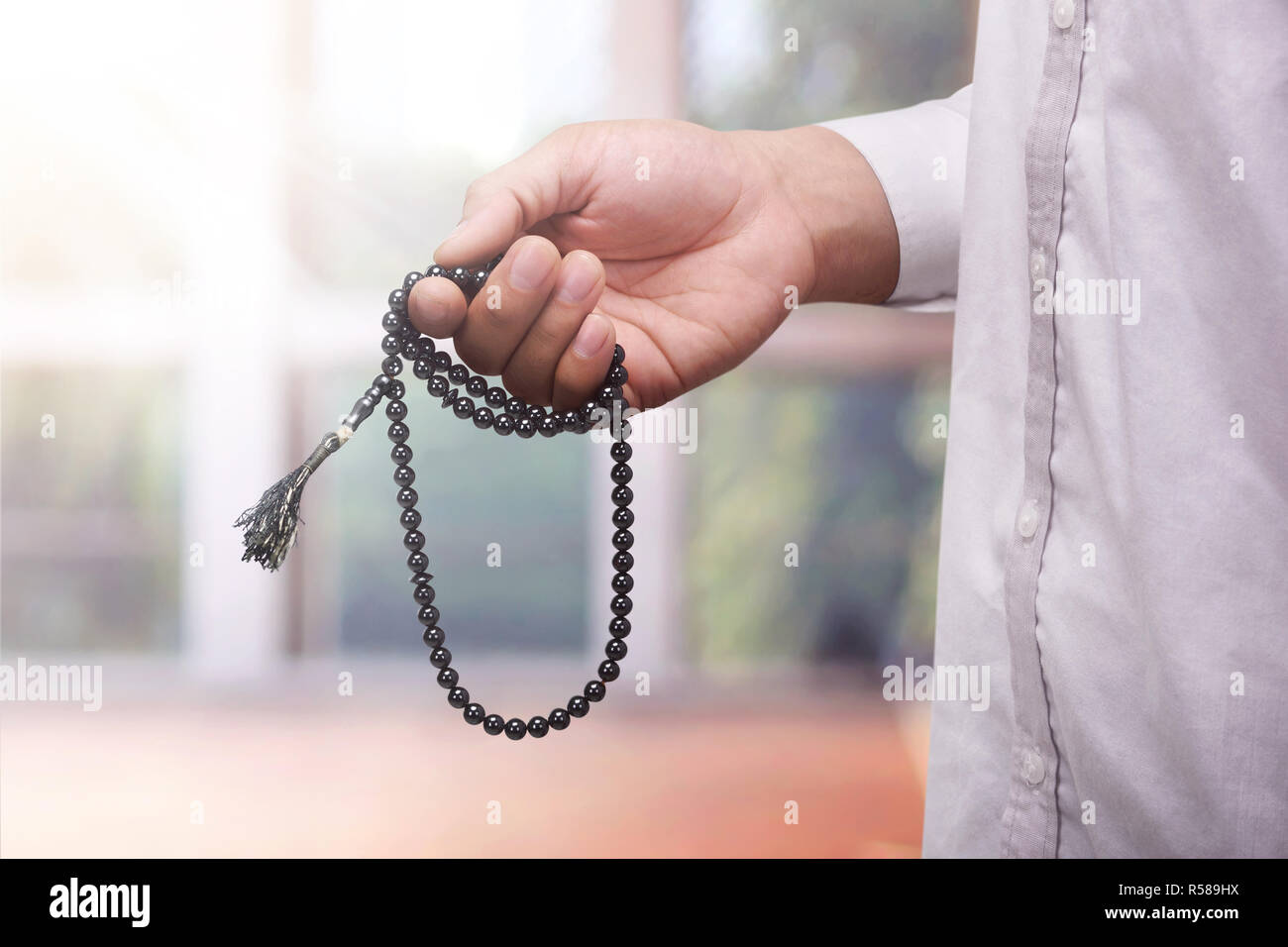 Hand of muslim man praying while holding tasbih Stock Photo - Alamy