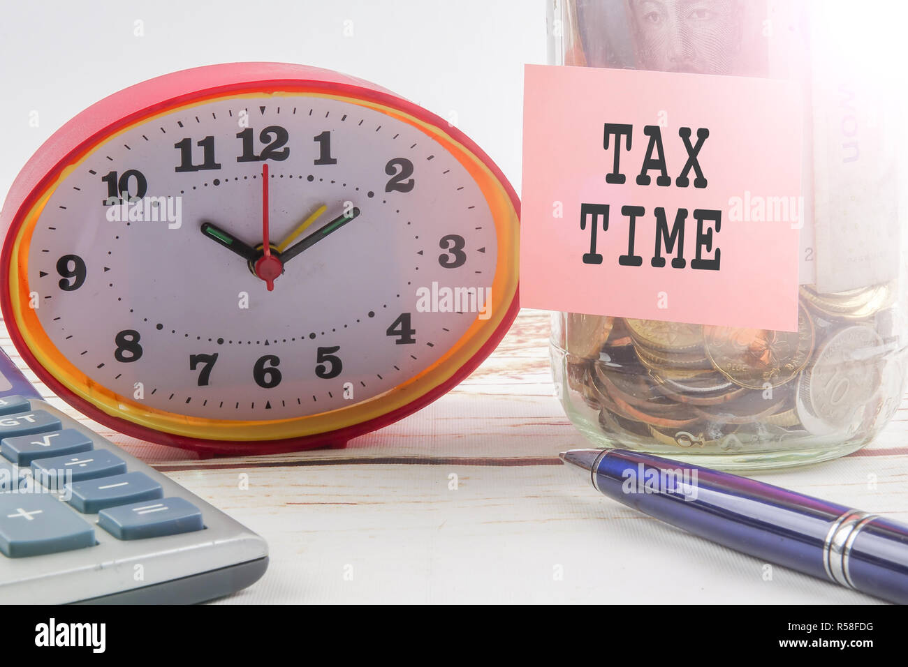 TAX DAY CONCEPT; Clock,red note,calculator and coins in the mason jar ...