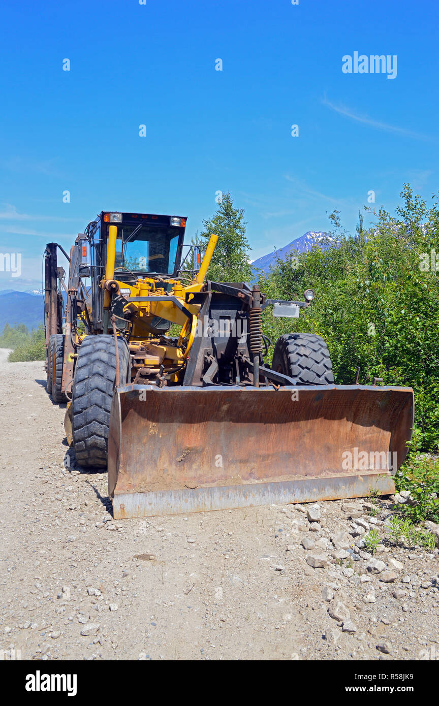 Grader on dusty gravel road Stock Photo - Alamy