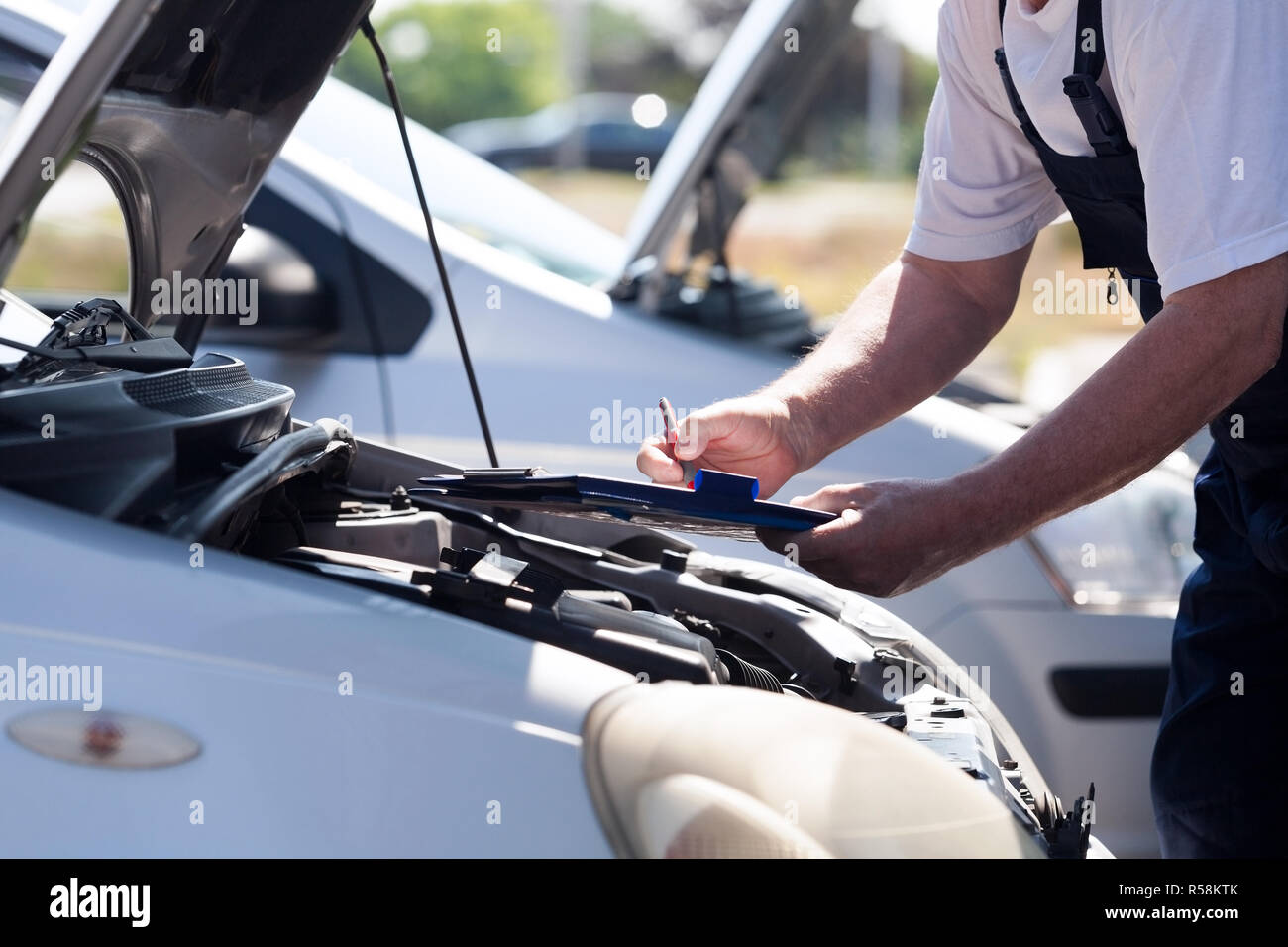 Auto mechanic checking car engine and writing on the clipboard Stock ...