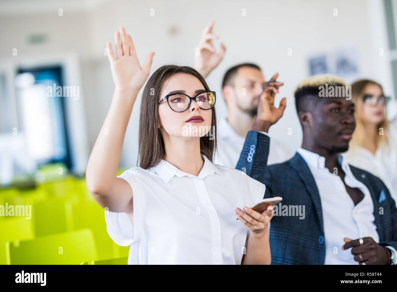 Business people at the conference raising hands to answer a question ...