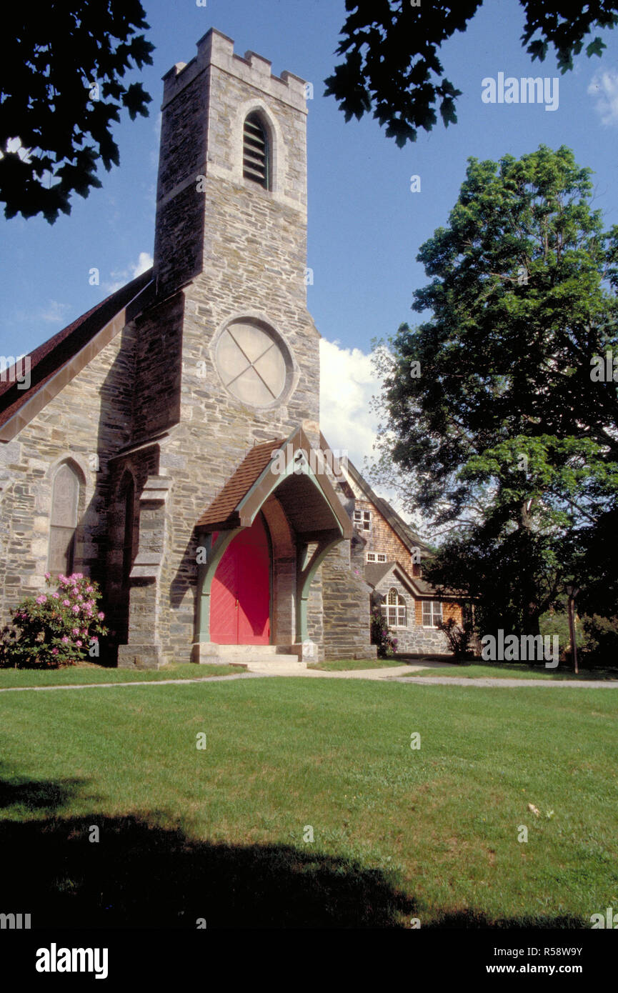 A red door, circular window, and bell tower mark the entrance of this ...