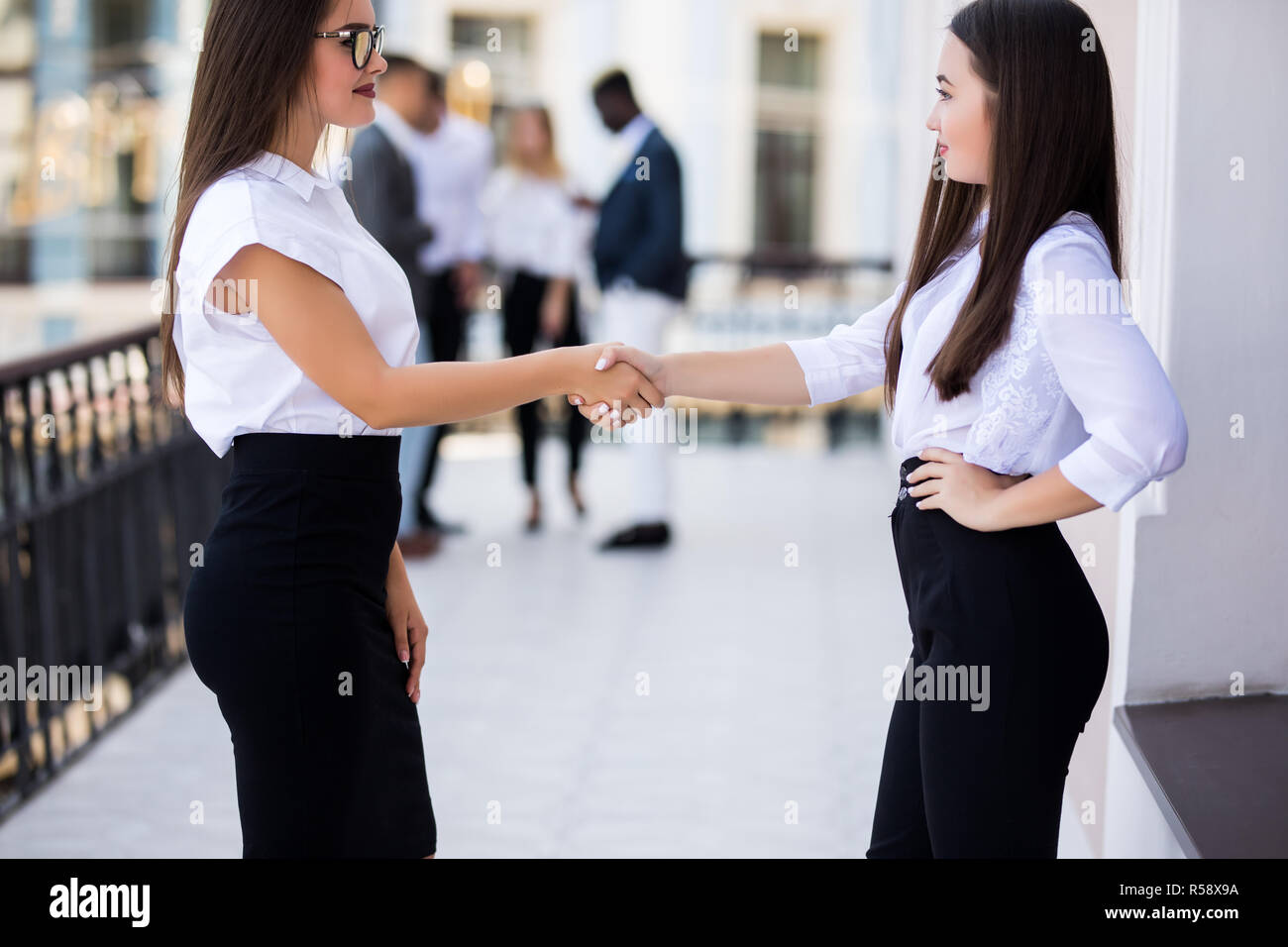 two beautiful businesswomen handshaking in office Stock Photo - Alamy