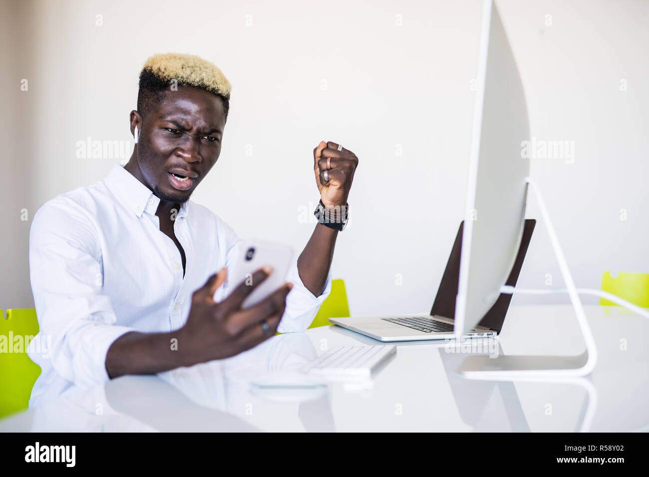 Angry businessman working and talking on mobile phone at office desk ...