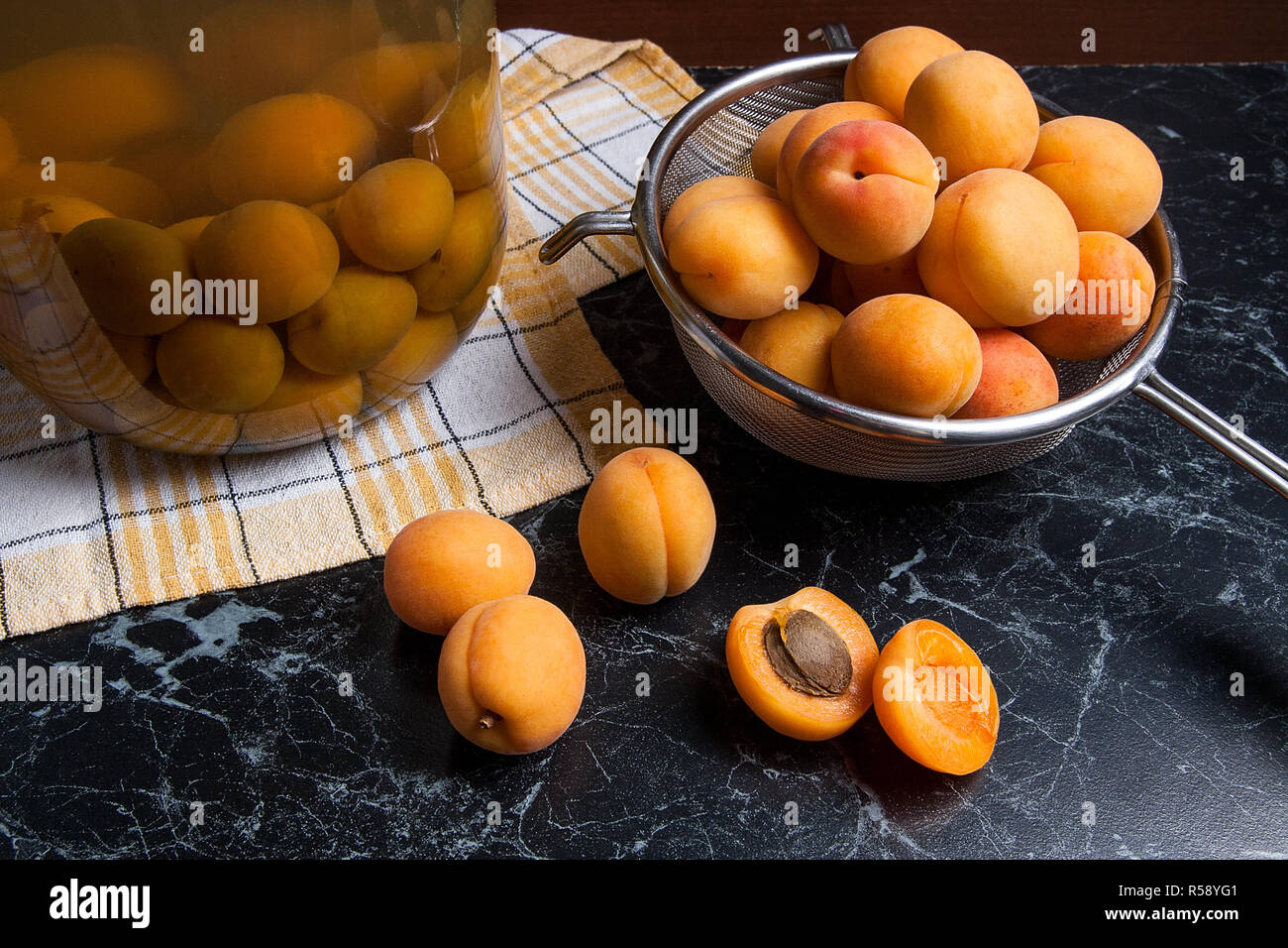 Ripe organic apricots harvested at summer time and big glass jar with ...