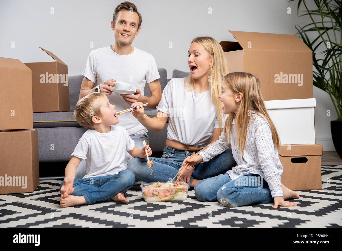 Photo of happy couple with children eating rice with shrimps sitting on ...