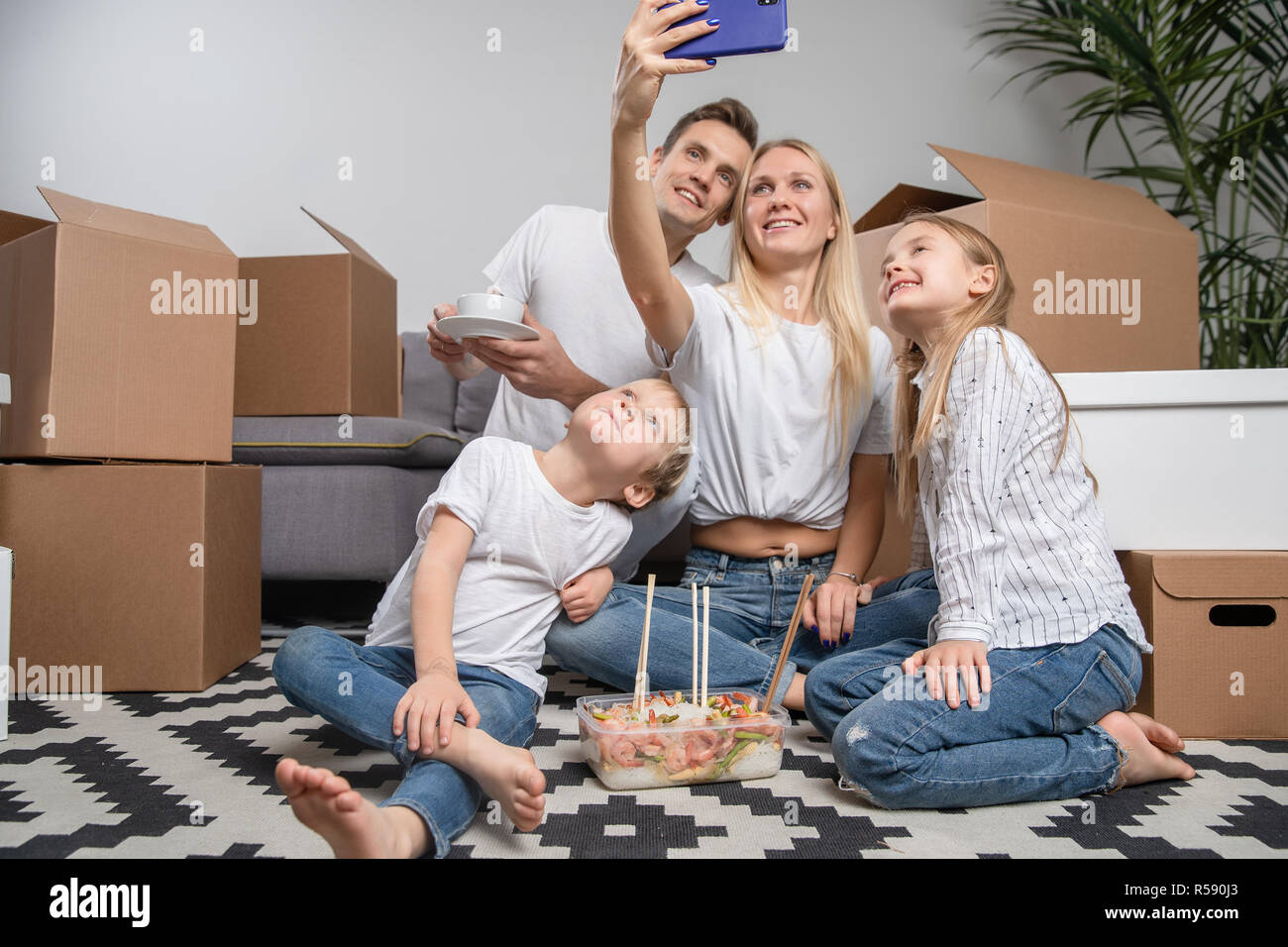 Photo of man, children and women taking selfie sitting on floor among ...
