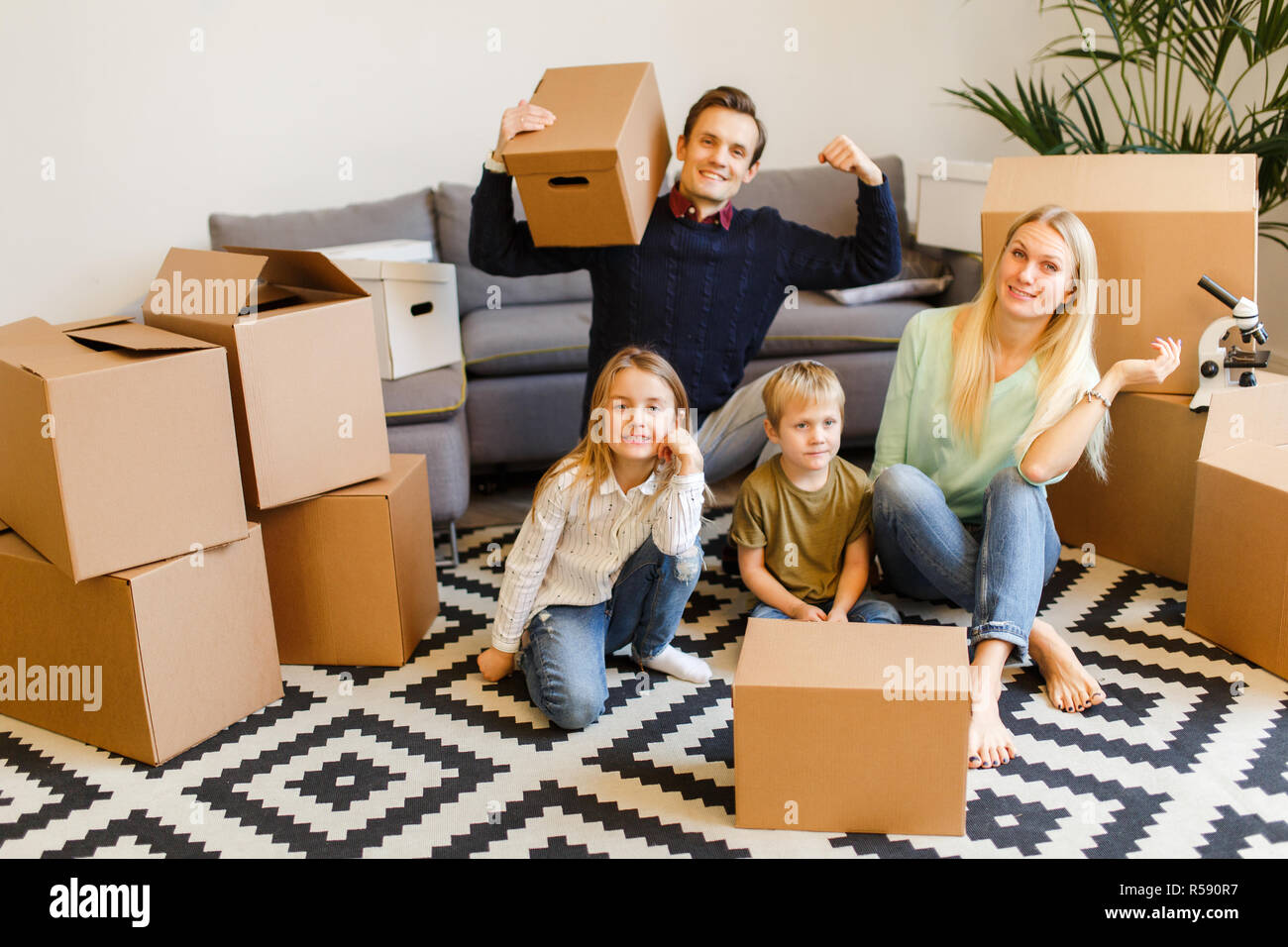 Image of parents with children sitting on floor among cardboard boxes ...