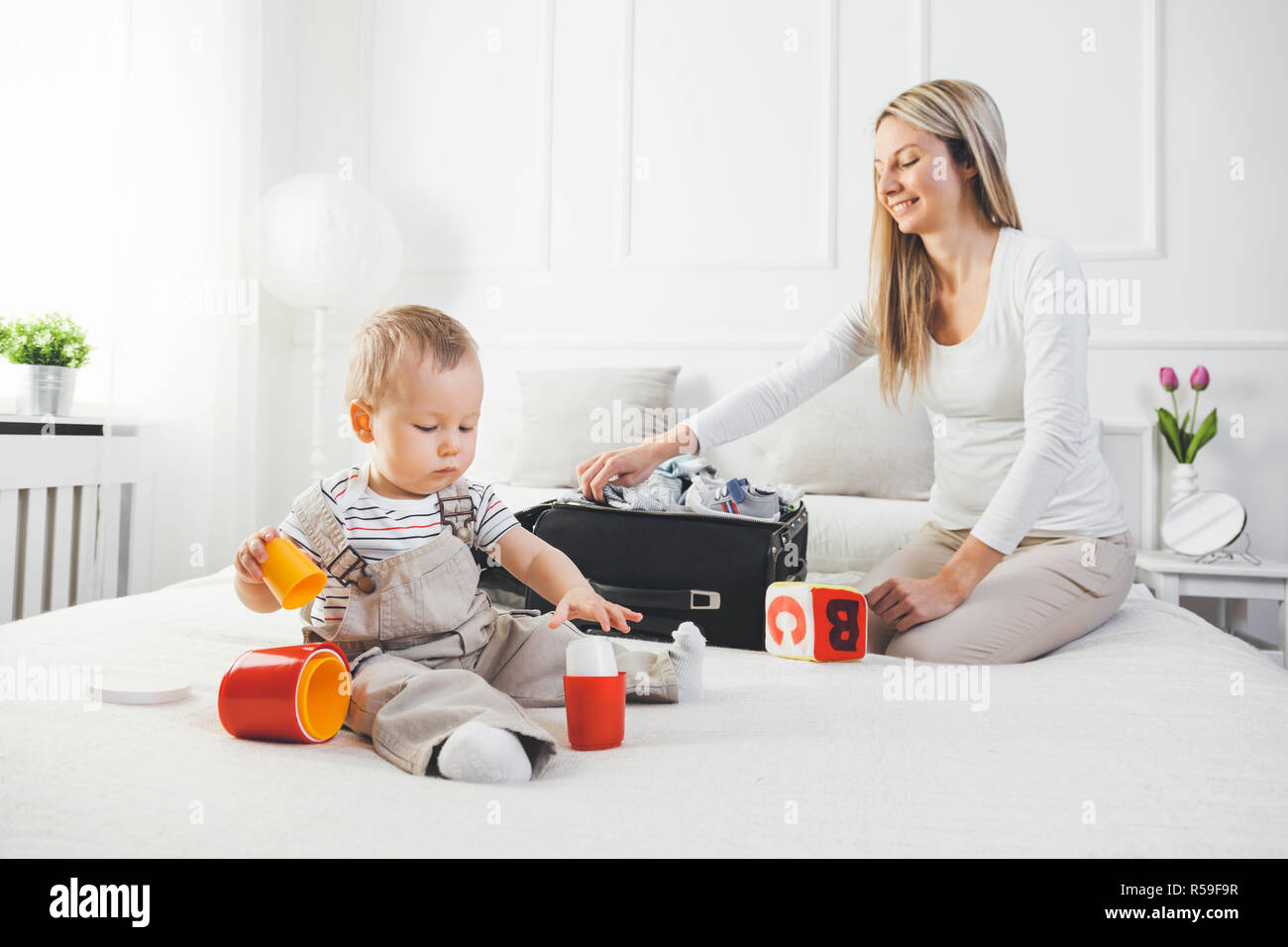 Travelling with kids. Happy mother with her child packing clothes for ...