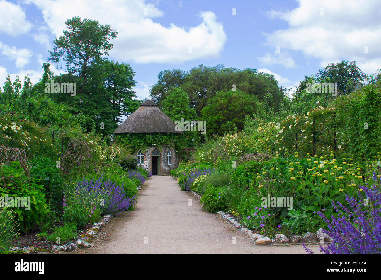 The 19th Century thatched round house surrounded by beautiful flower ...
