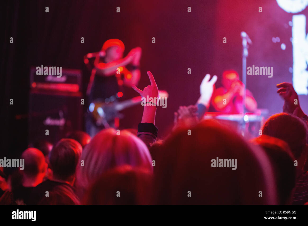 Silhouettes of a concert crowd in front of an illuminated stage in a ...