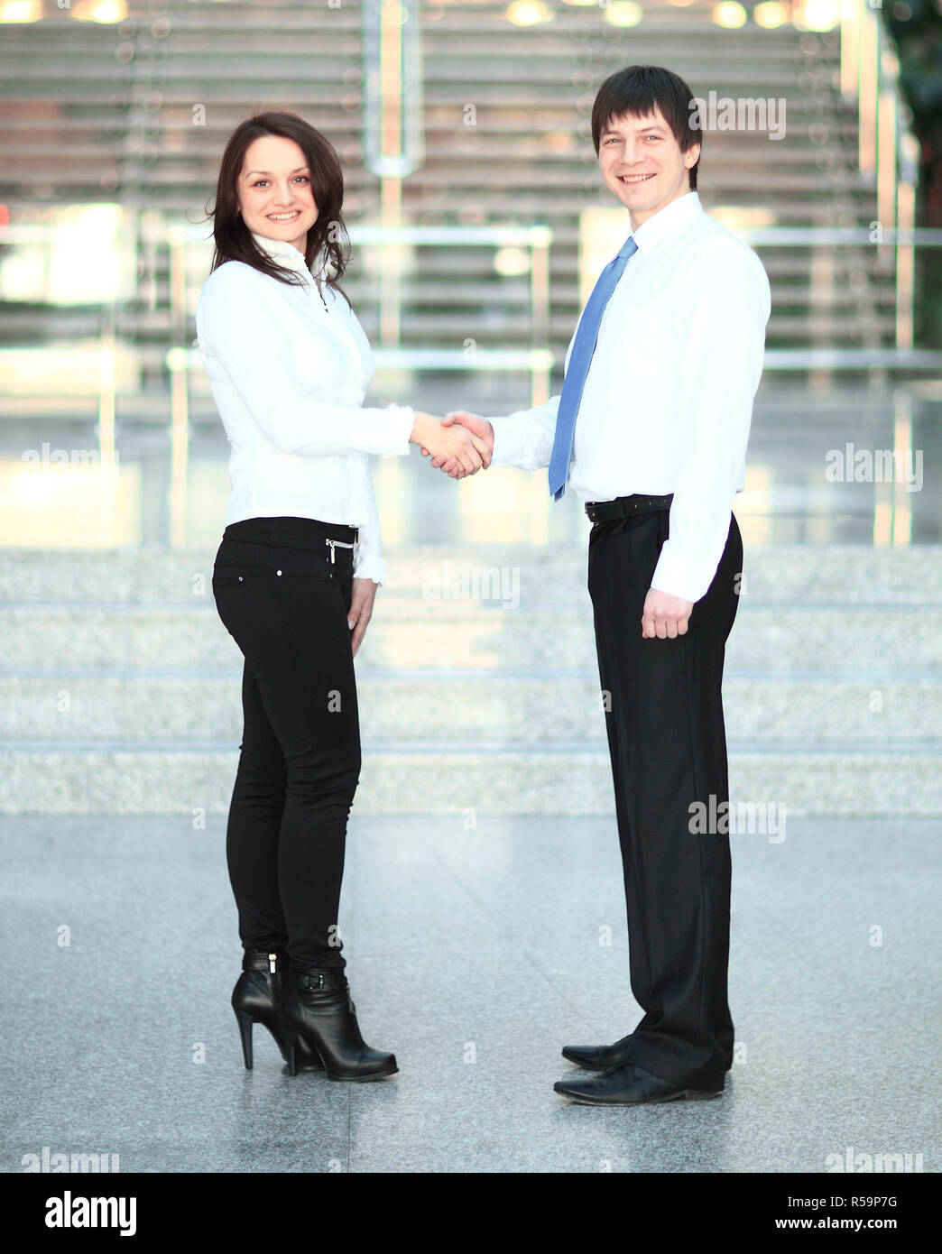 welcome handshake of young business partners on the background of the office Stock Photo - Alamy