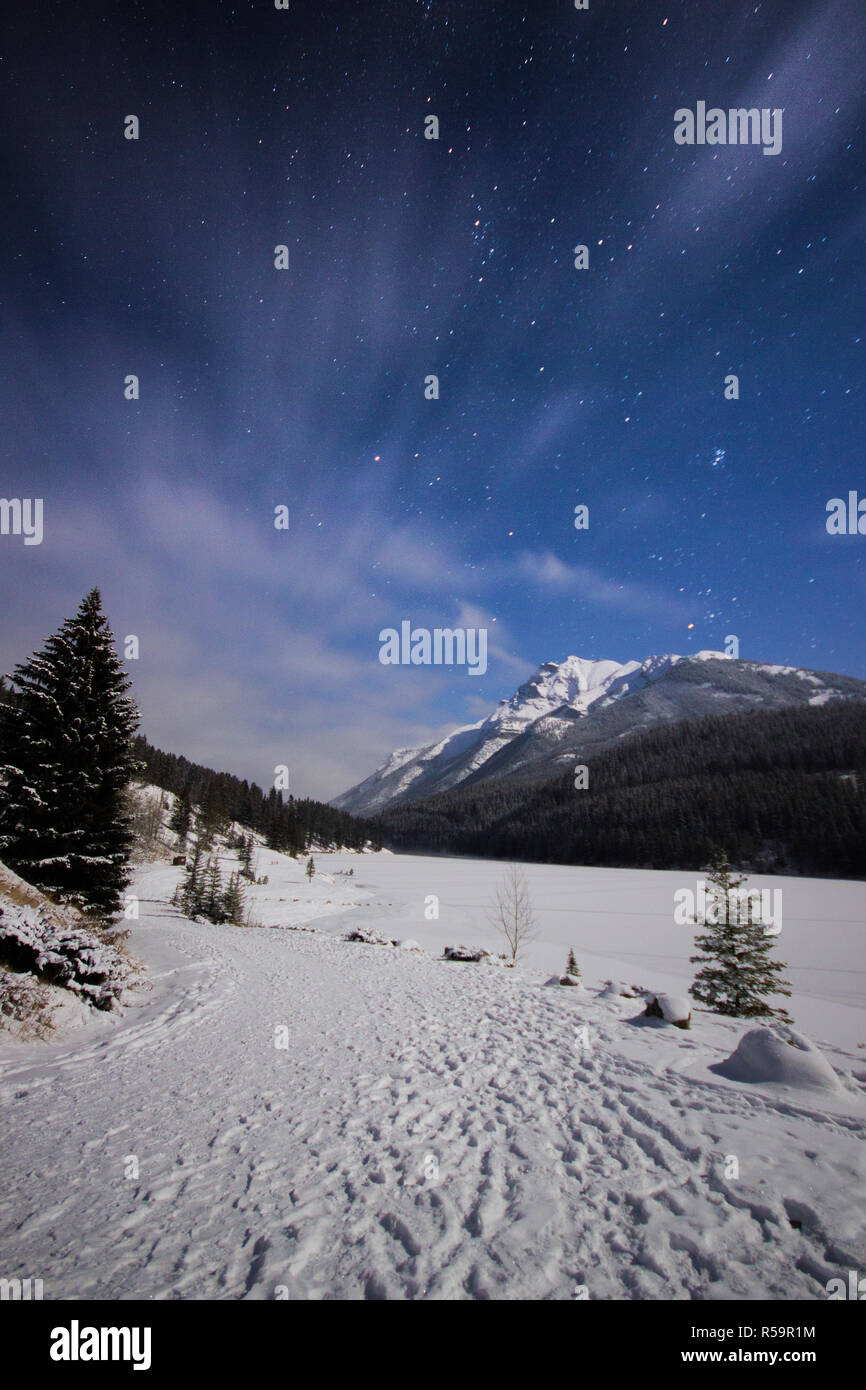 Frozen lake and snowy path in mountains during cold night under sky ...