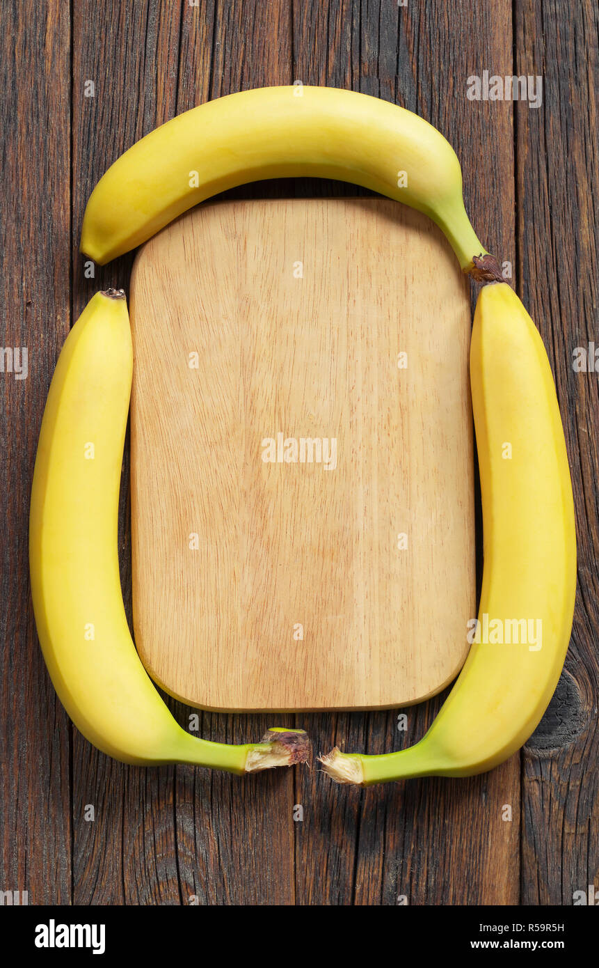 Bananas on an dark wooden table and cutting board with space for text ...