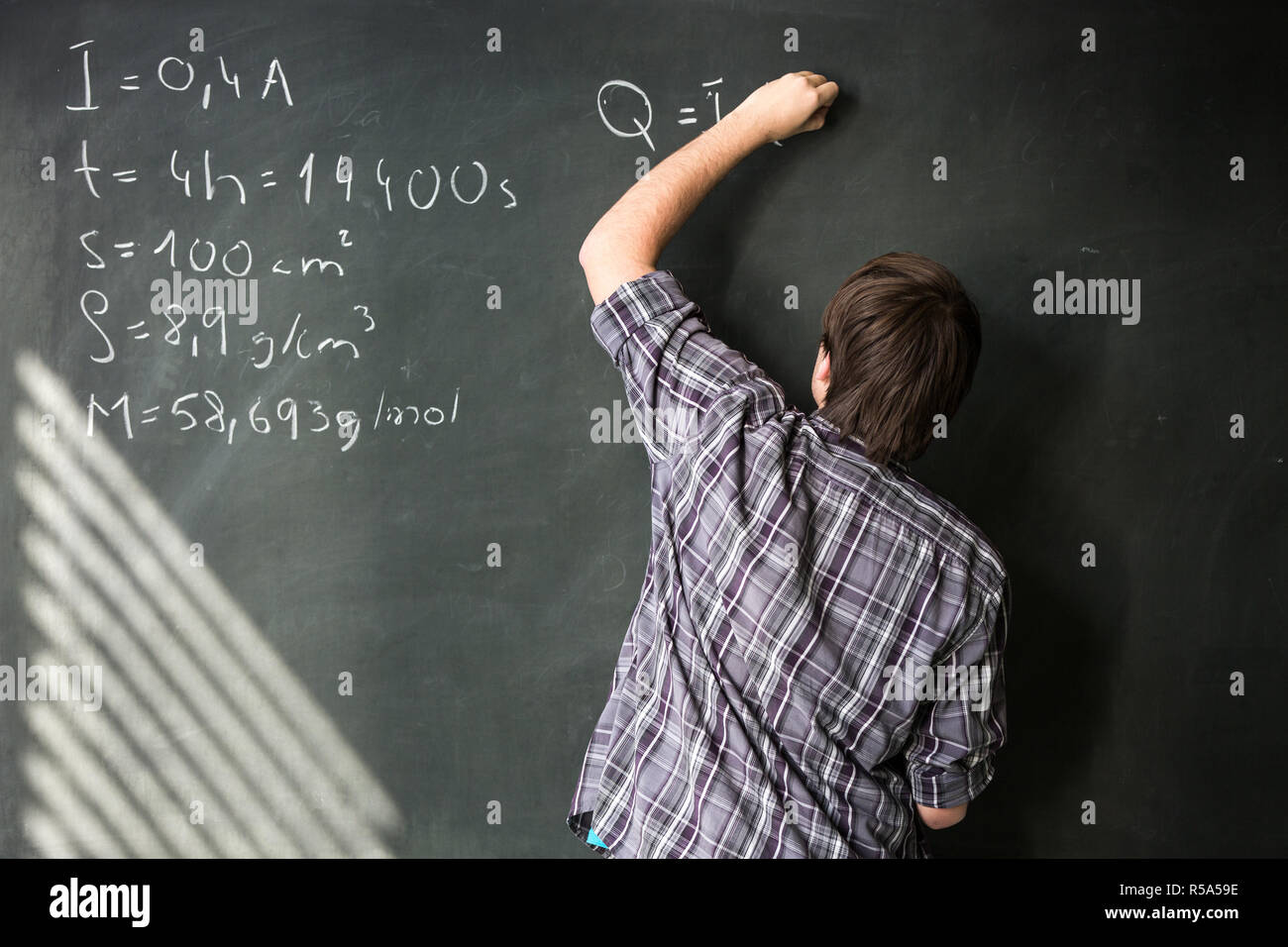 College student solving a math problem during math class in front of ...