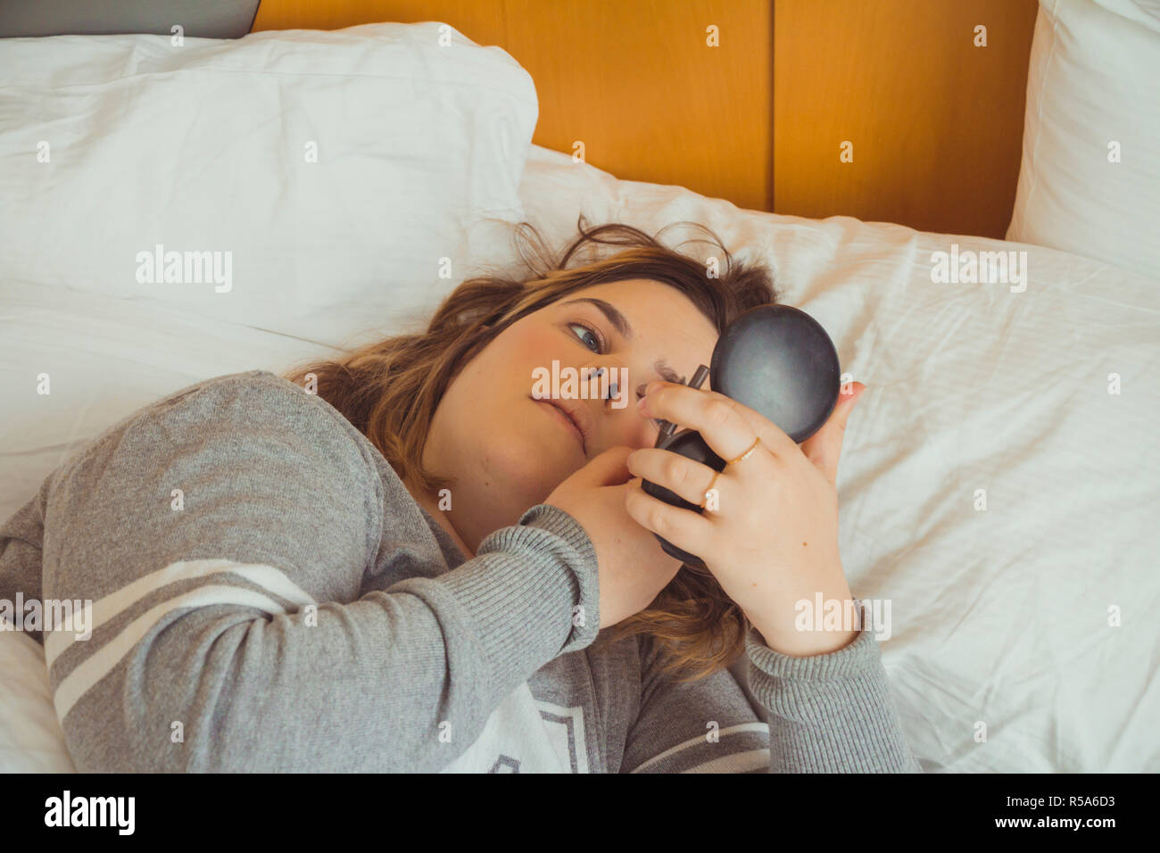 Woman applying makeup while she is lying on her bed Stock Photo - Alamy