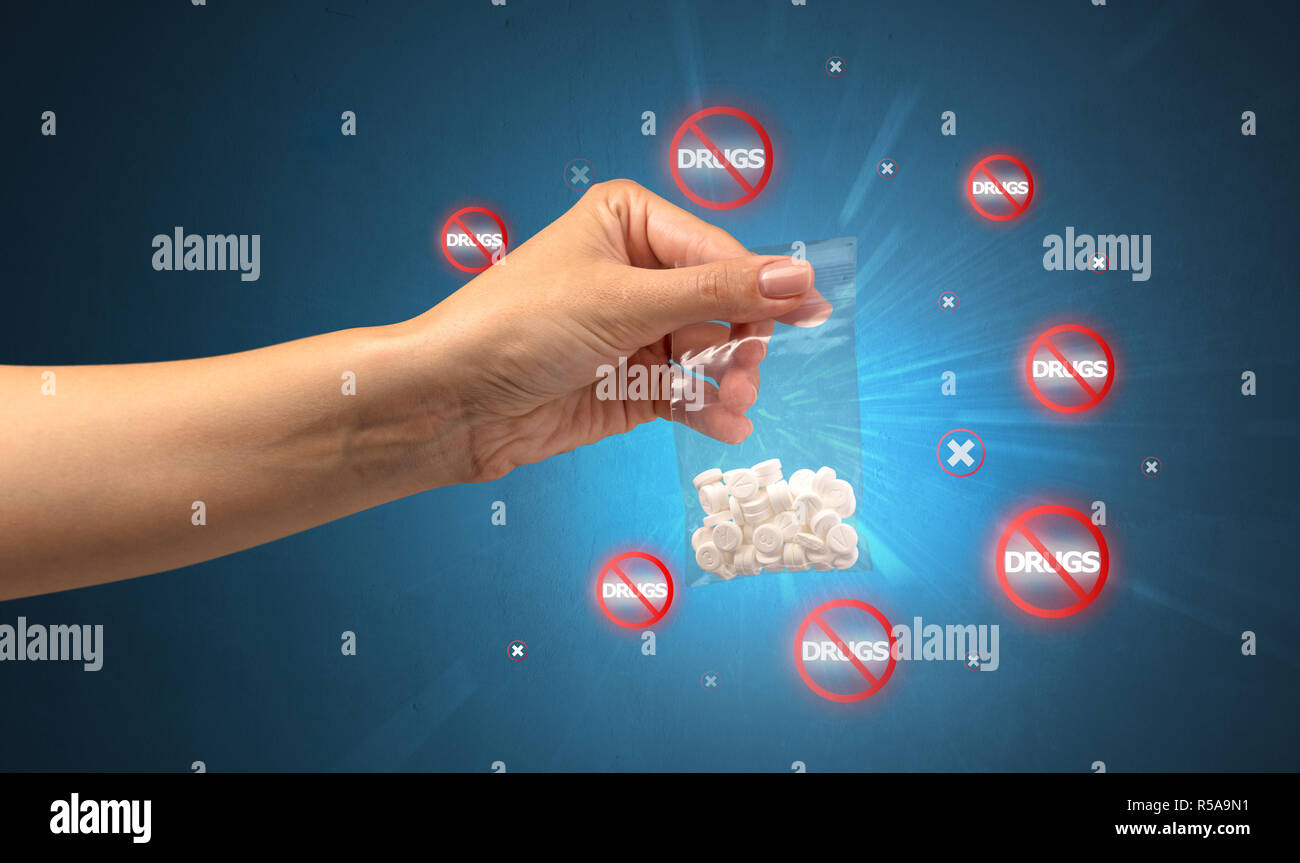Hand giving pills with anti-drug concept and not allowed signs around ...