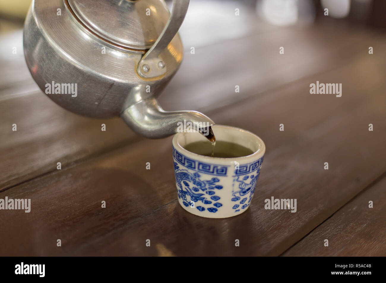 Teapot pouring tea into a cup Stock Photo - Alamy