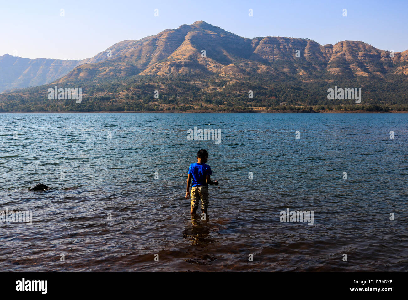 A boy playing with water in Mula river. It is located in the Mulshi ...