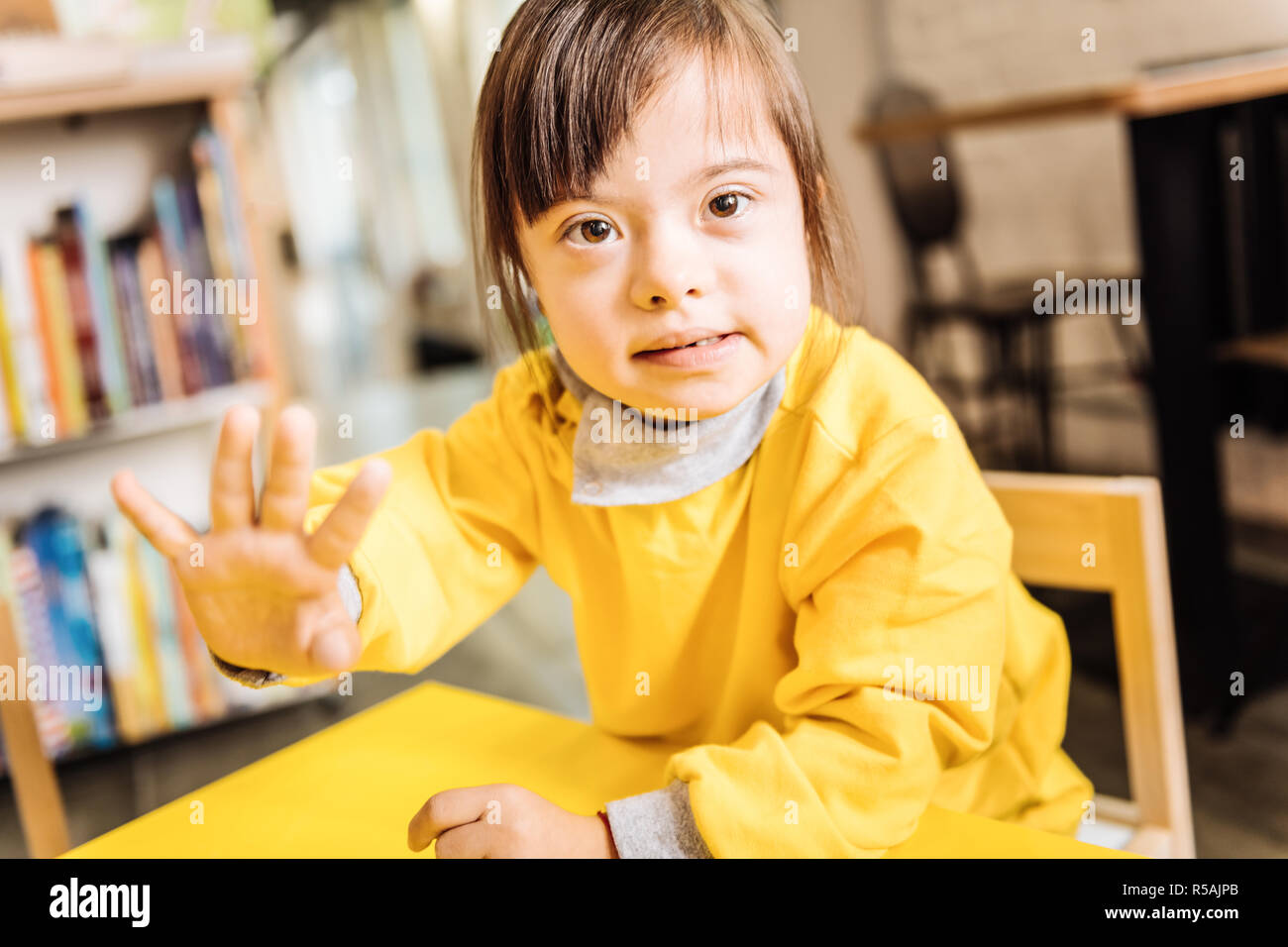 Showing palm. Dark-eyed beautiful preschool girl with genetic disorder ...