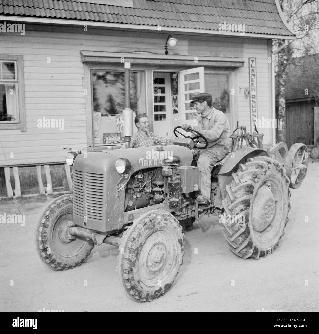 Farmer on TAKRA tractor talking to man village shop store Finland 1955 ...
