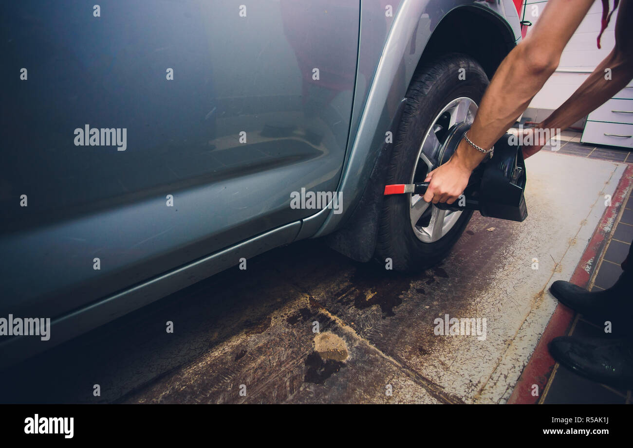 Mechanic tuning aligner for wheel alignment in garage closeup ...