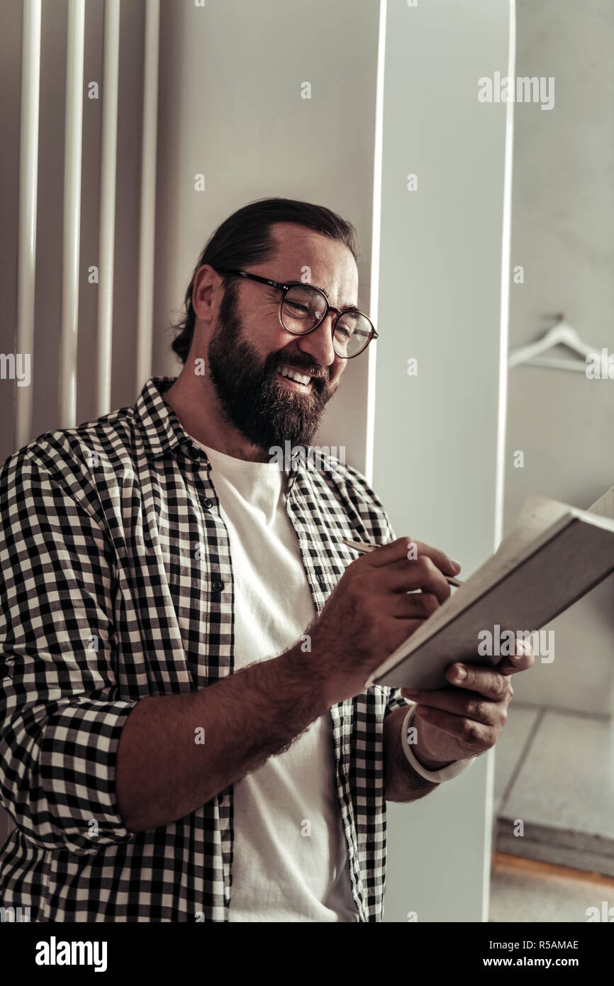 Daily schedule. Cheerful happy man holding a notebook while planning ...
