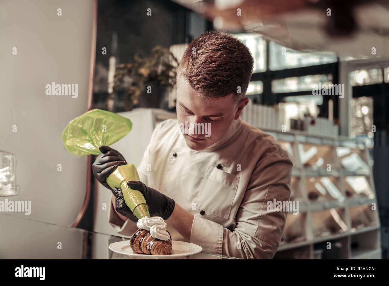 Professional confectioner. Smart nice man using a pastry bag while ...
